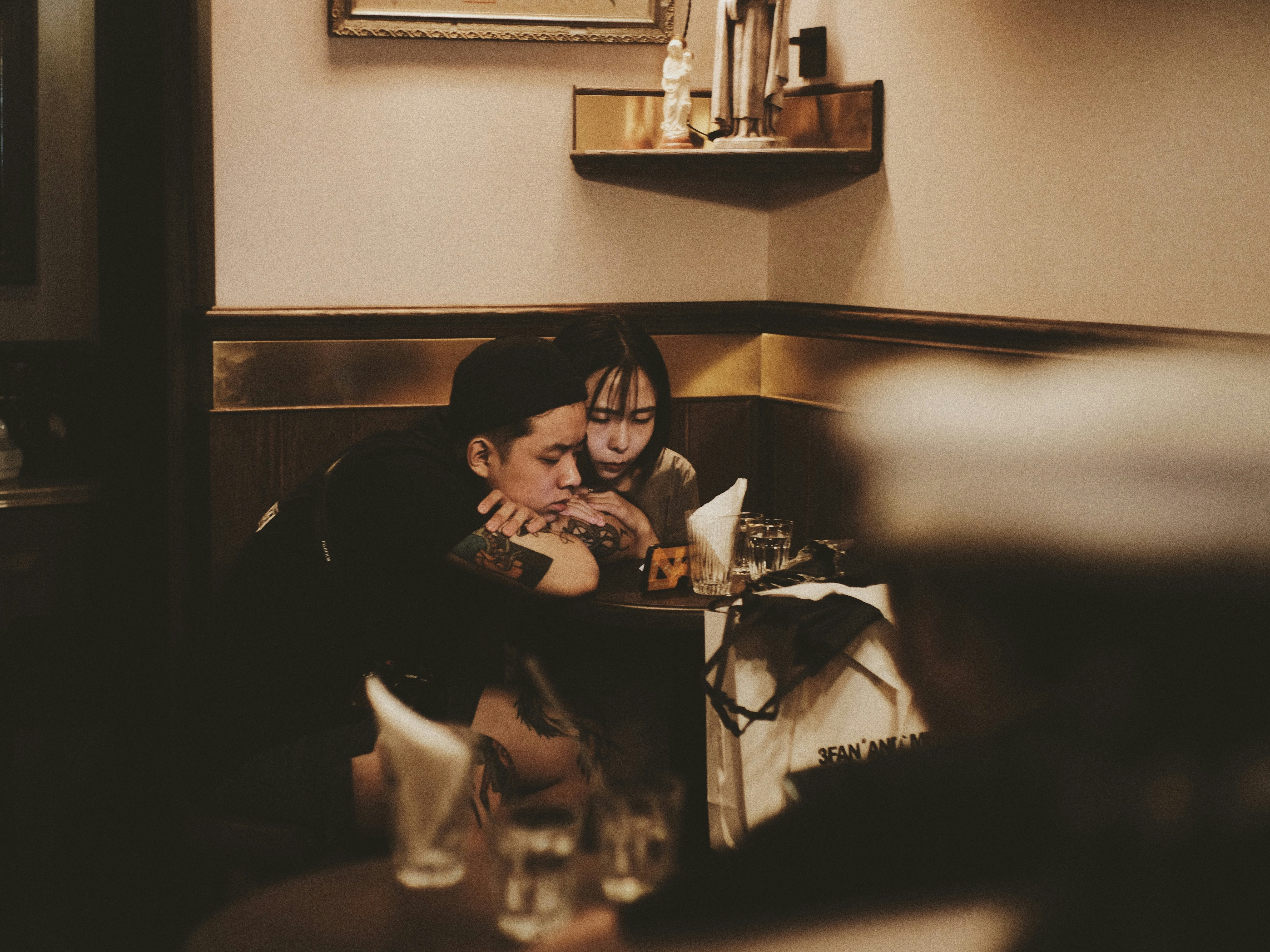 Soft Hushed Moment: Two Faces Lean in at a Cozy Café Booth