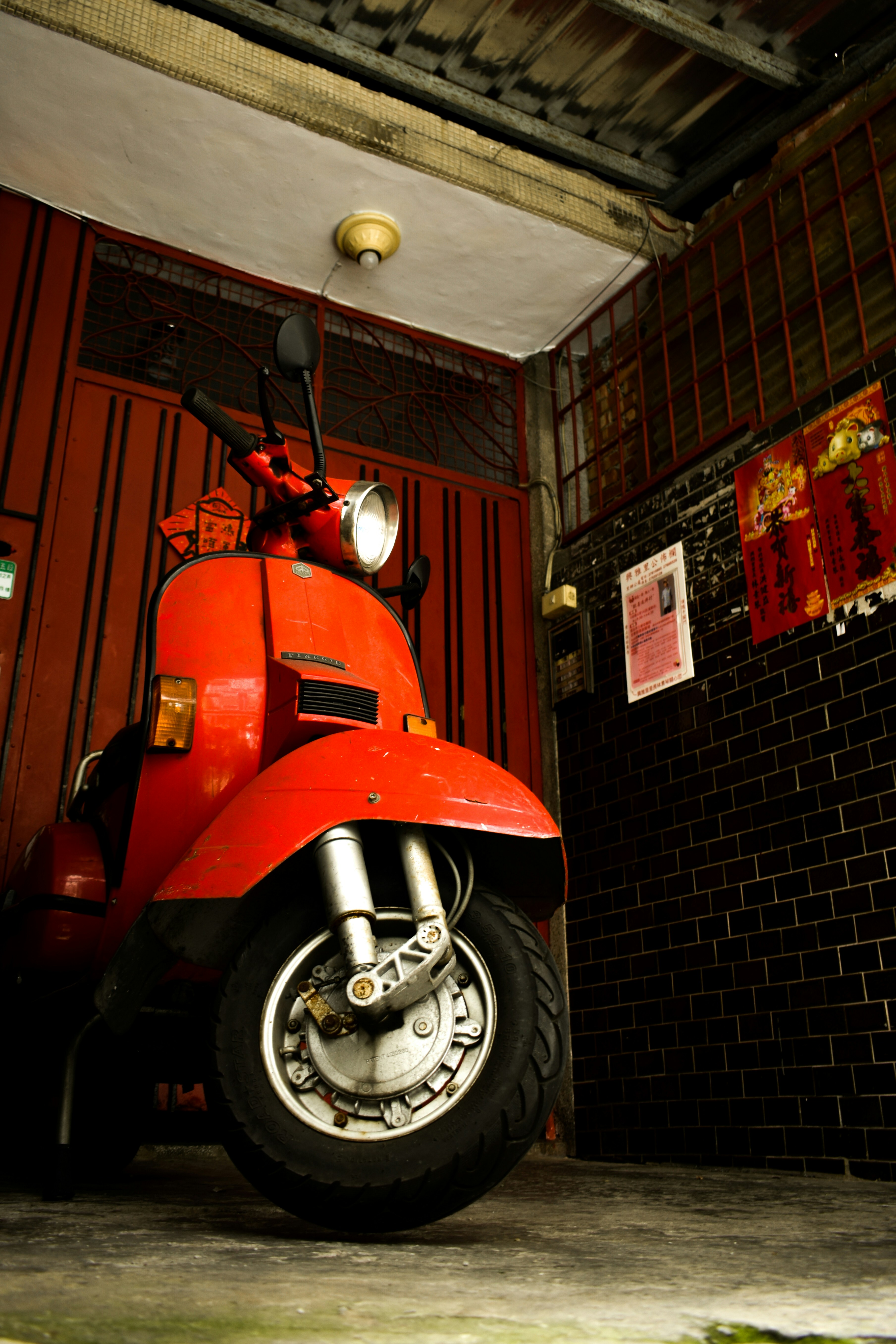 Scarlet Scooter in a Dim Tile-Walled Garage