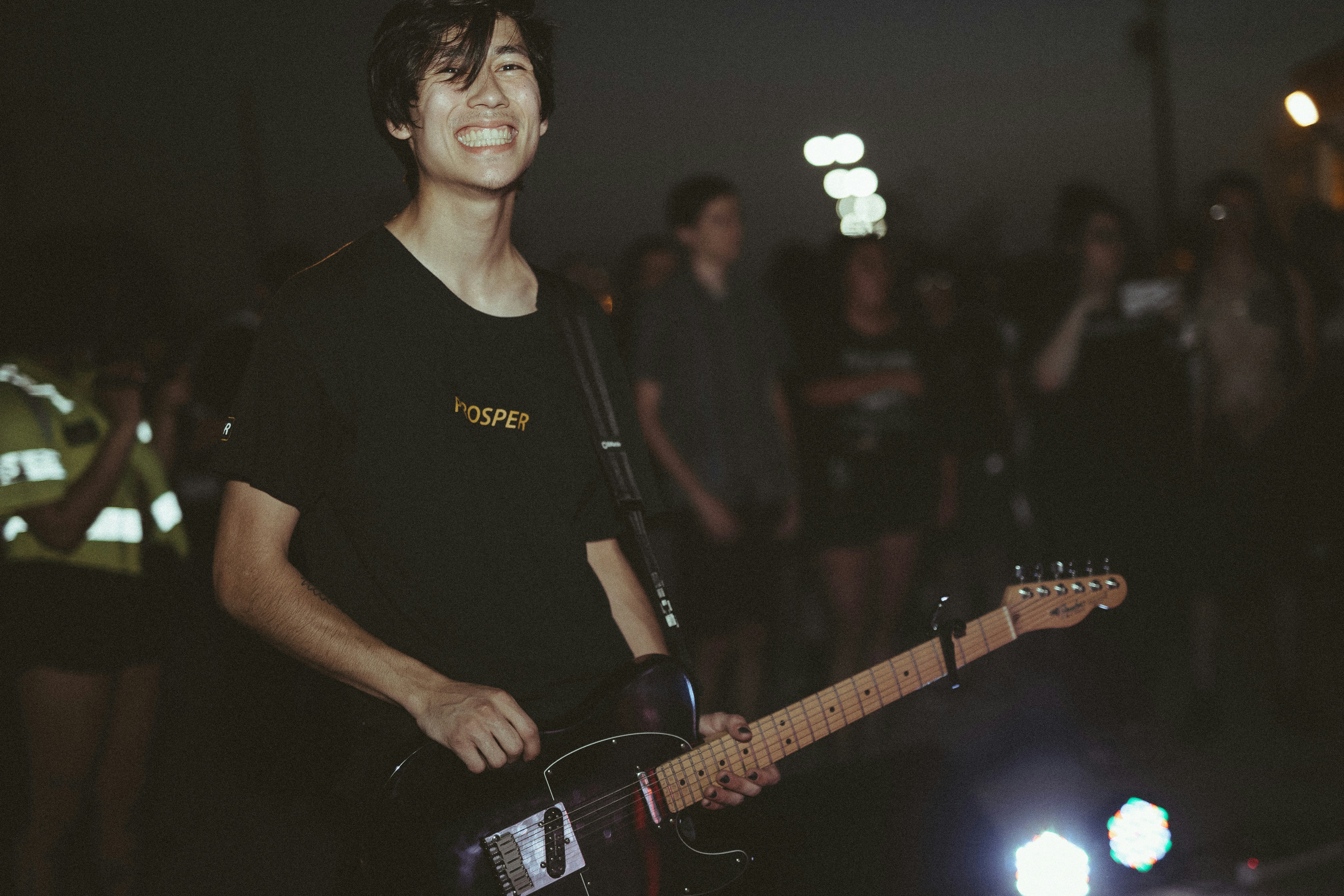 Night Stage Smile: A Guitarist Illuminated by Subtle Neon Glow