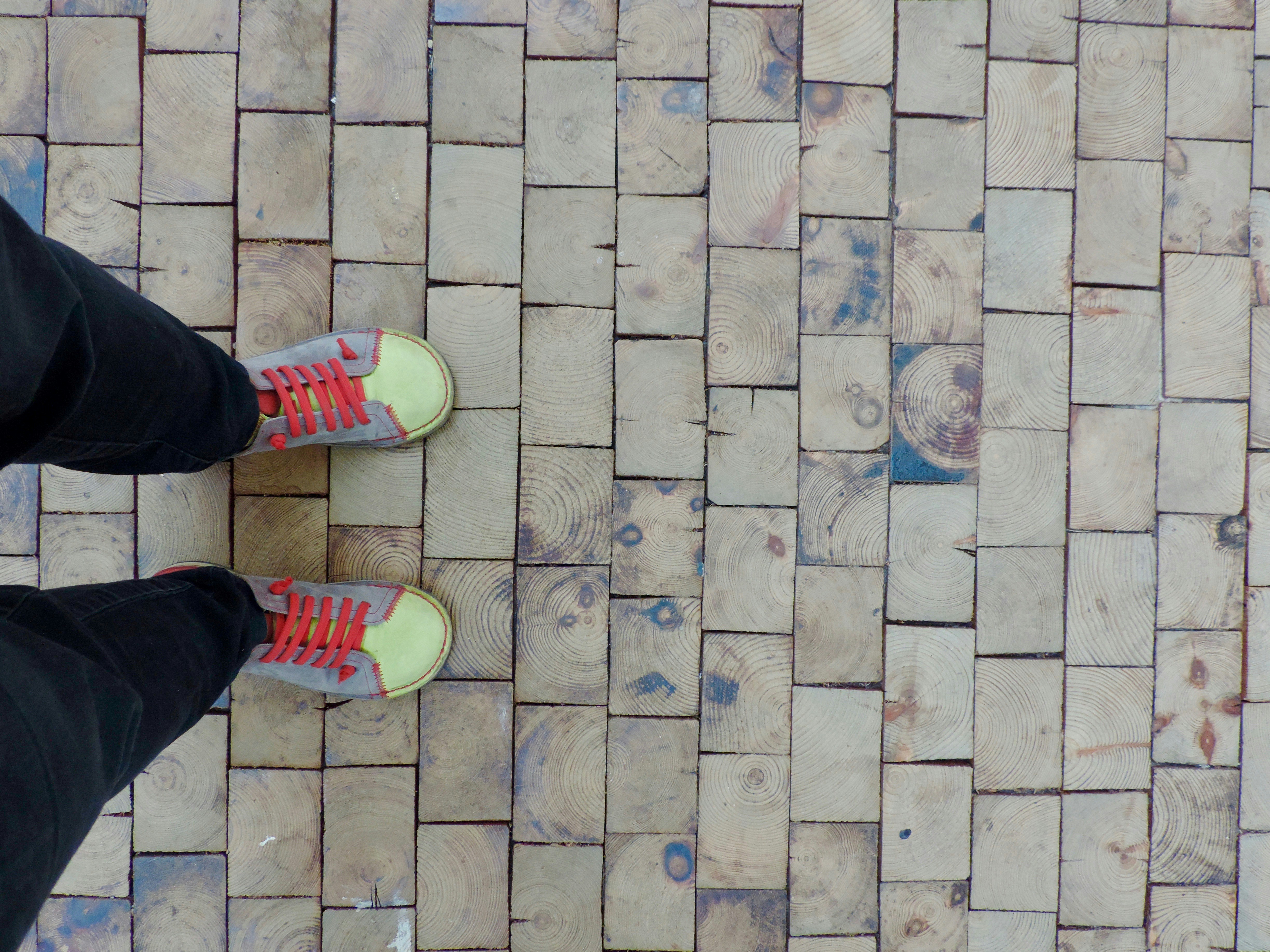 Colorful sneakers resting on a textured wooden floor, showcasing the natural patterns of the wood grain.