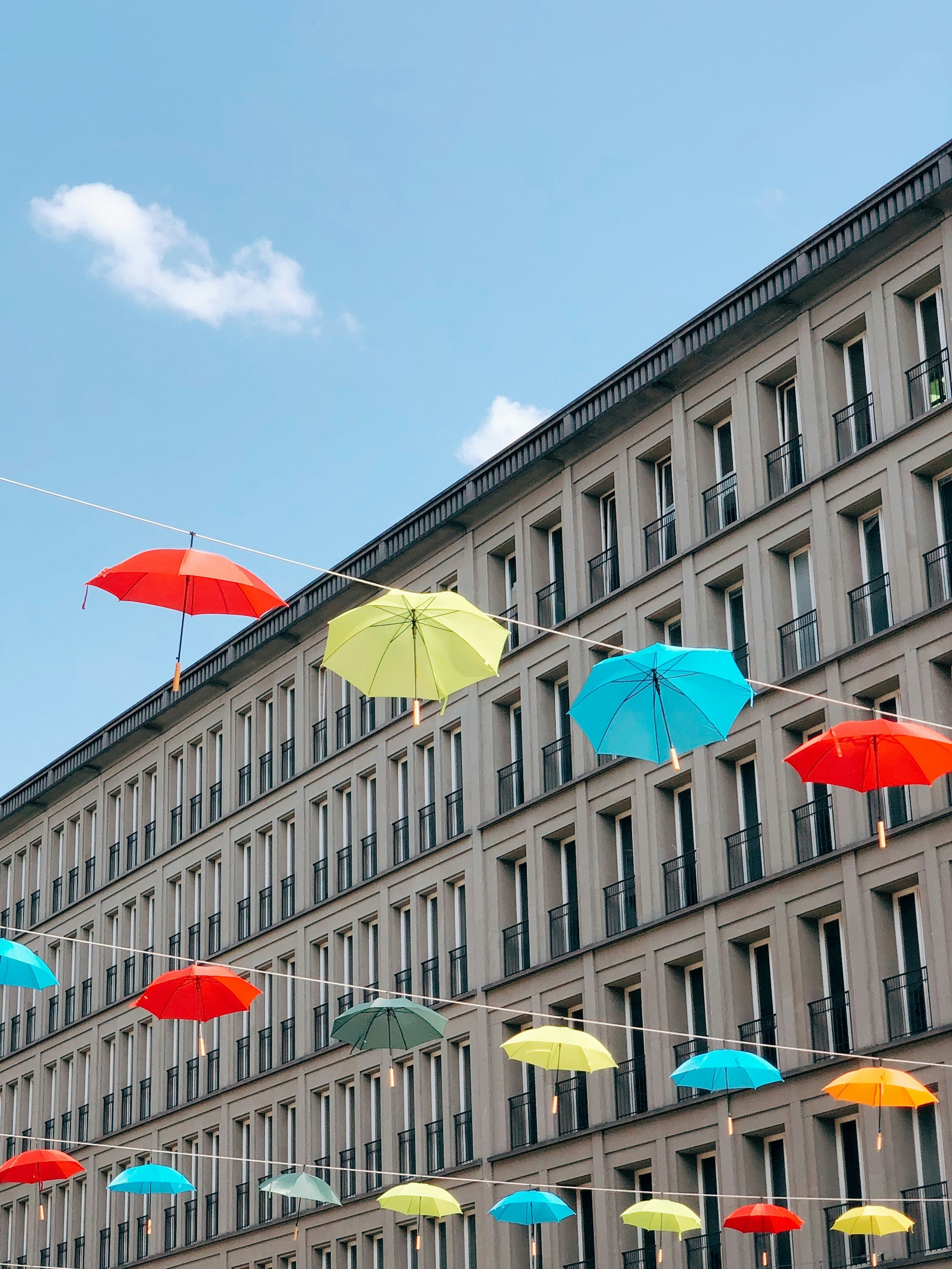 Colorful Umbrella Parade Above a Classic Facade