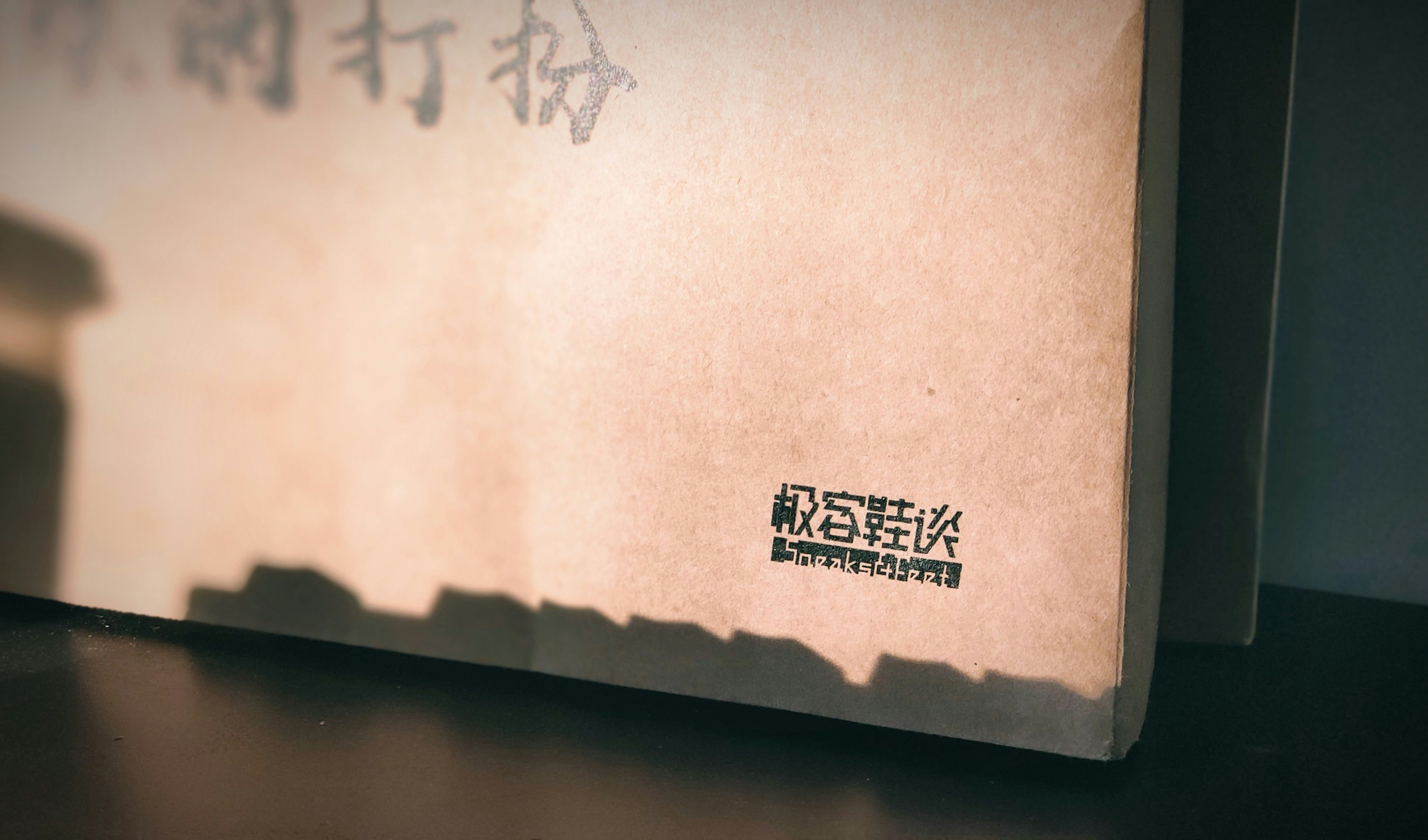 Close-up of a textured paper with elegant calligraphy and a stamped logo in the corner. The play of light and shadow enhances the depth and craftsmanship.