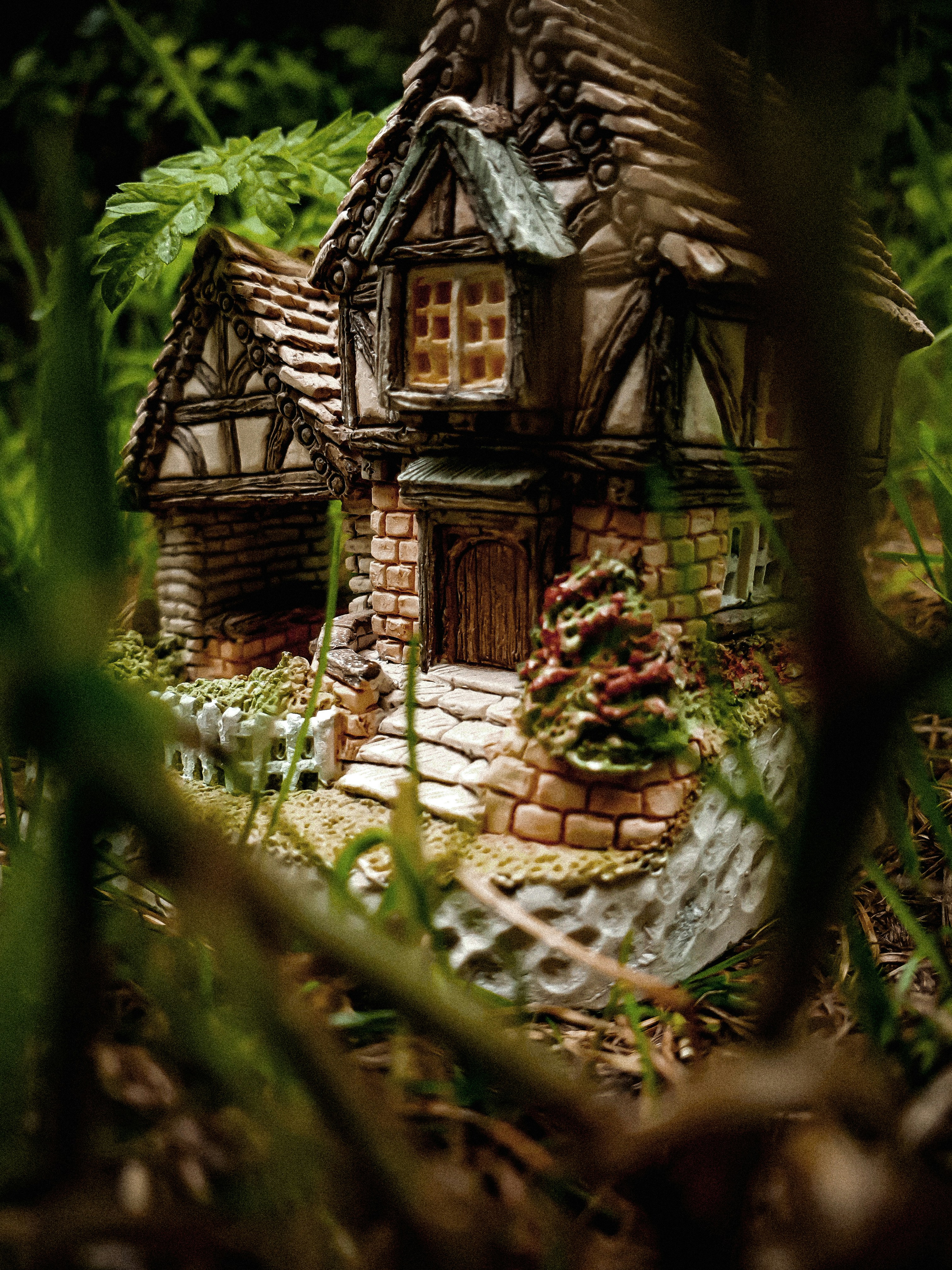 Intricately detailed miniature cottage surrounded by lush greenery, showcasing vibrant colors and textures. The scene captures a charming blend of craftsmanship and nature.