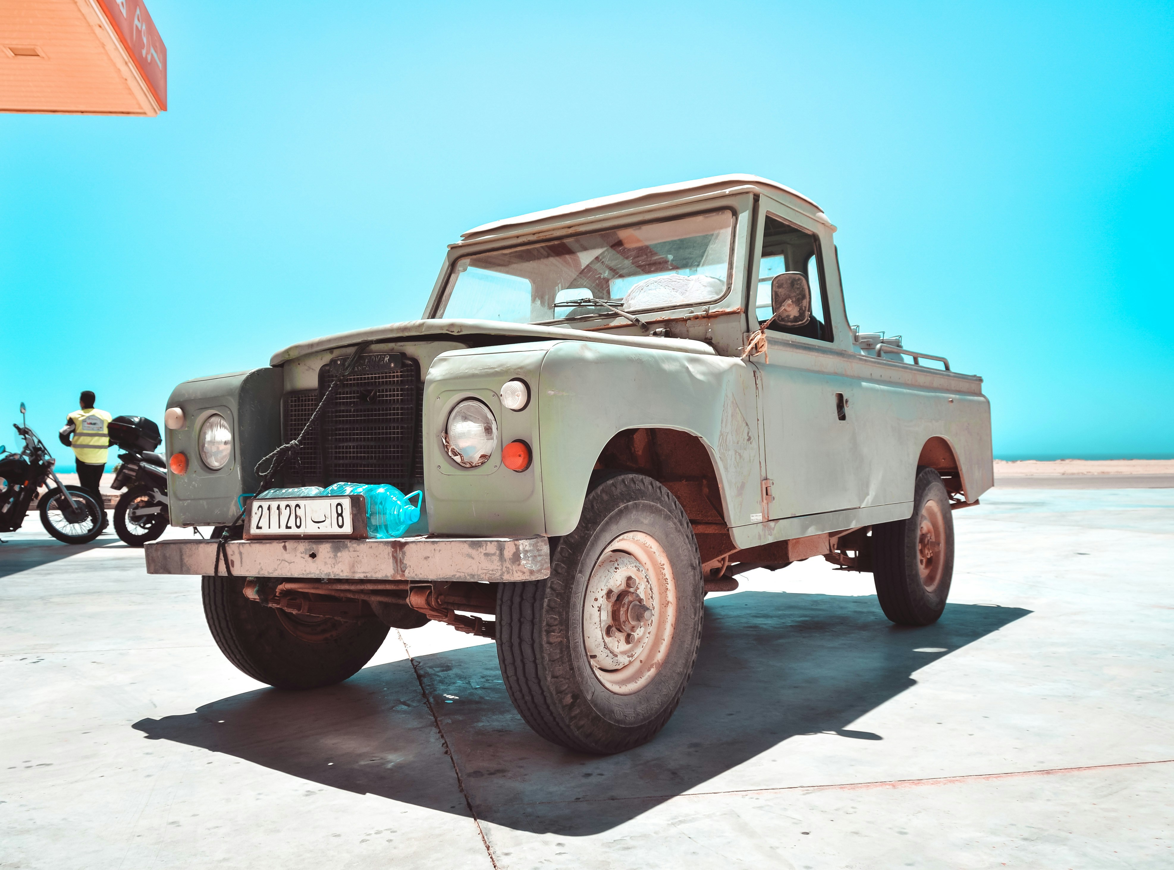 Classic green pickup truck parked under a bright blue sky, showcasing its vintage charm and rugged design.