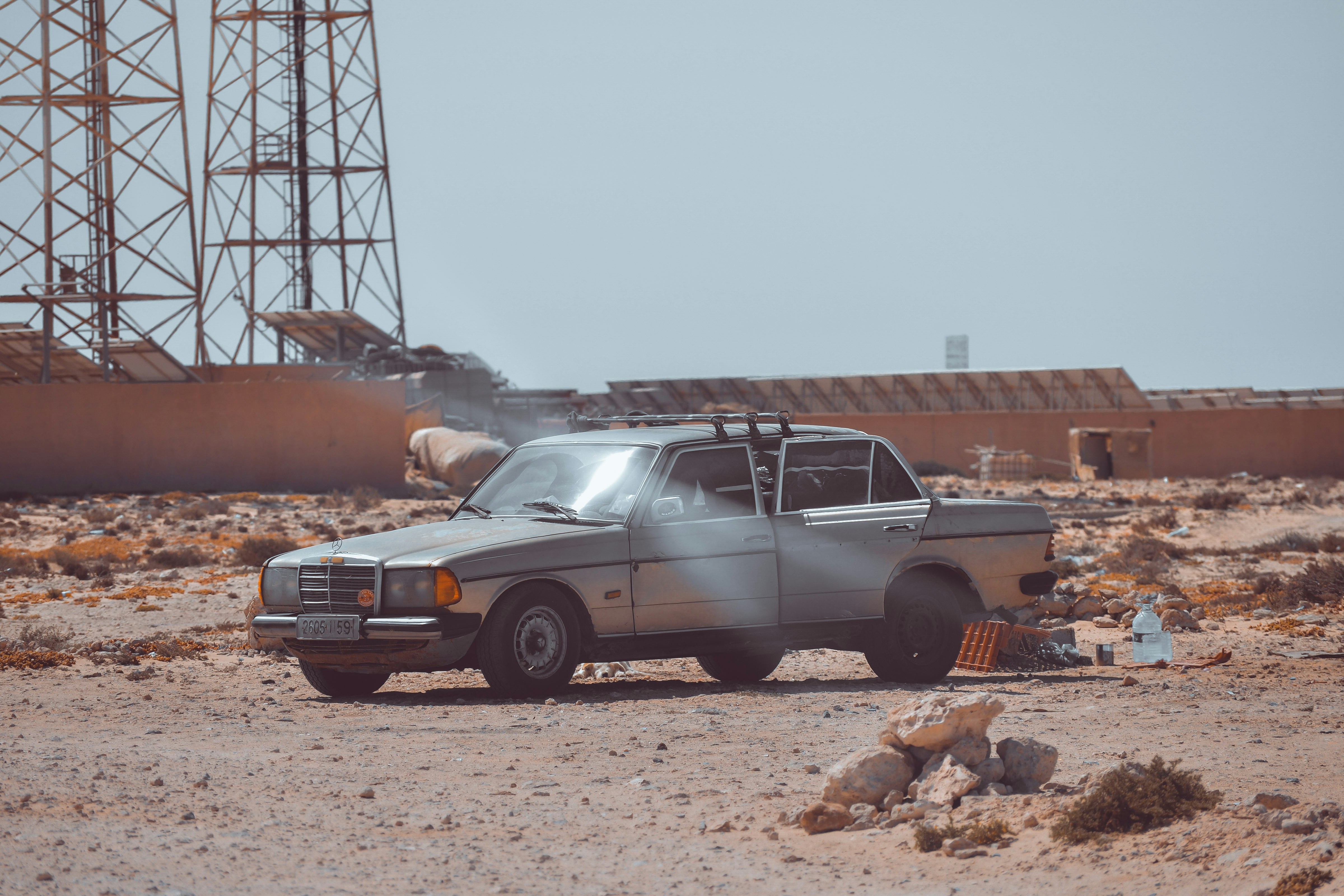 Desert Relic: A Weathered Sedan Beneath Rusted Towers