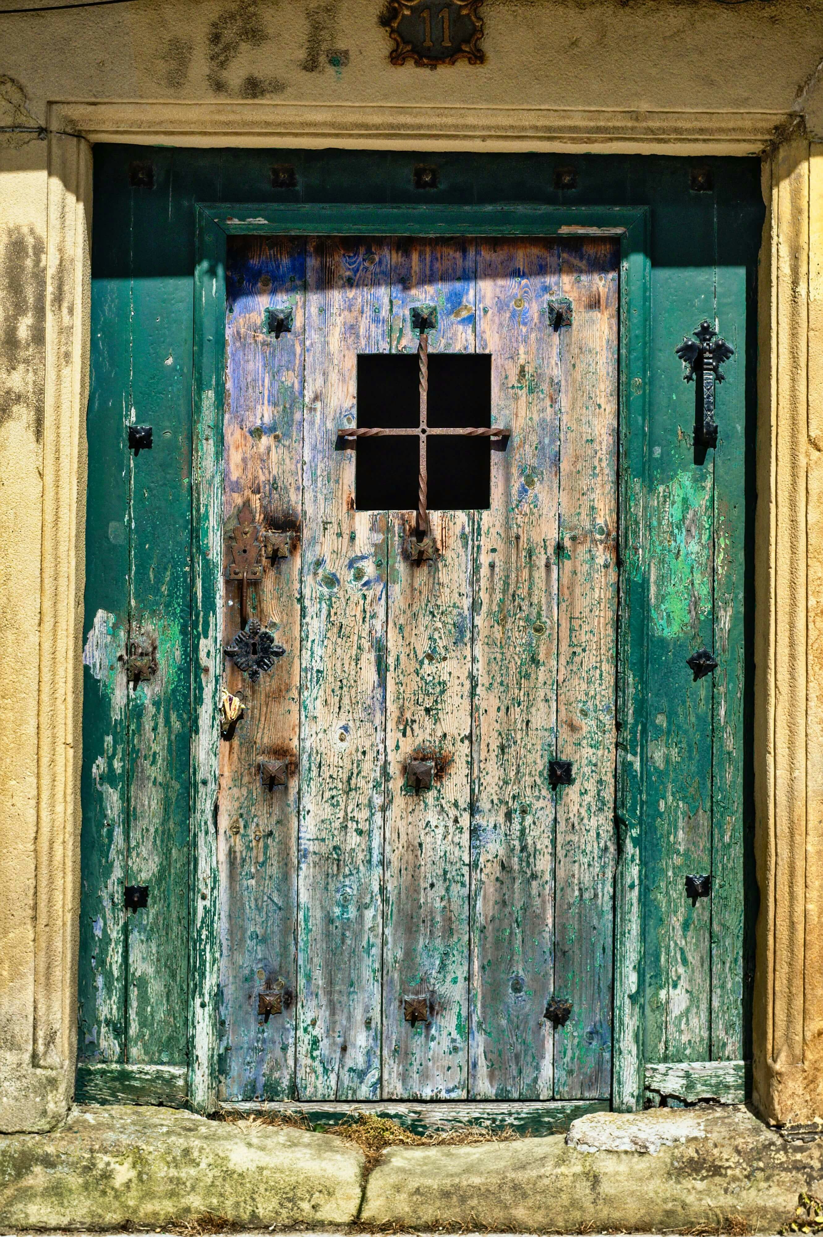 Aged Turquoise Portal: Weathered Planks, Iron Spikes, and a Square Crossed Window