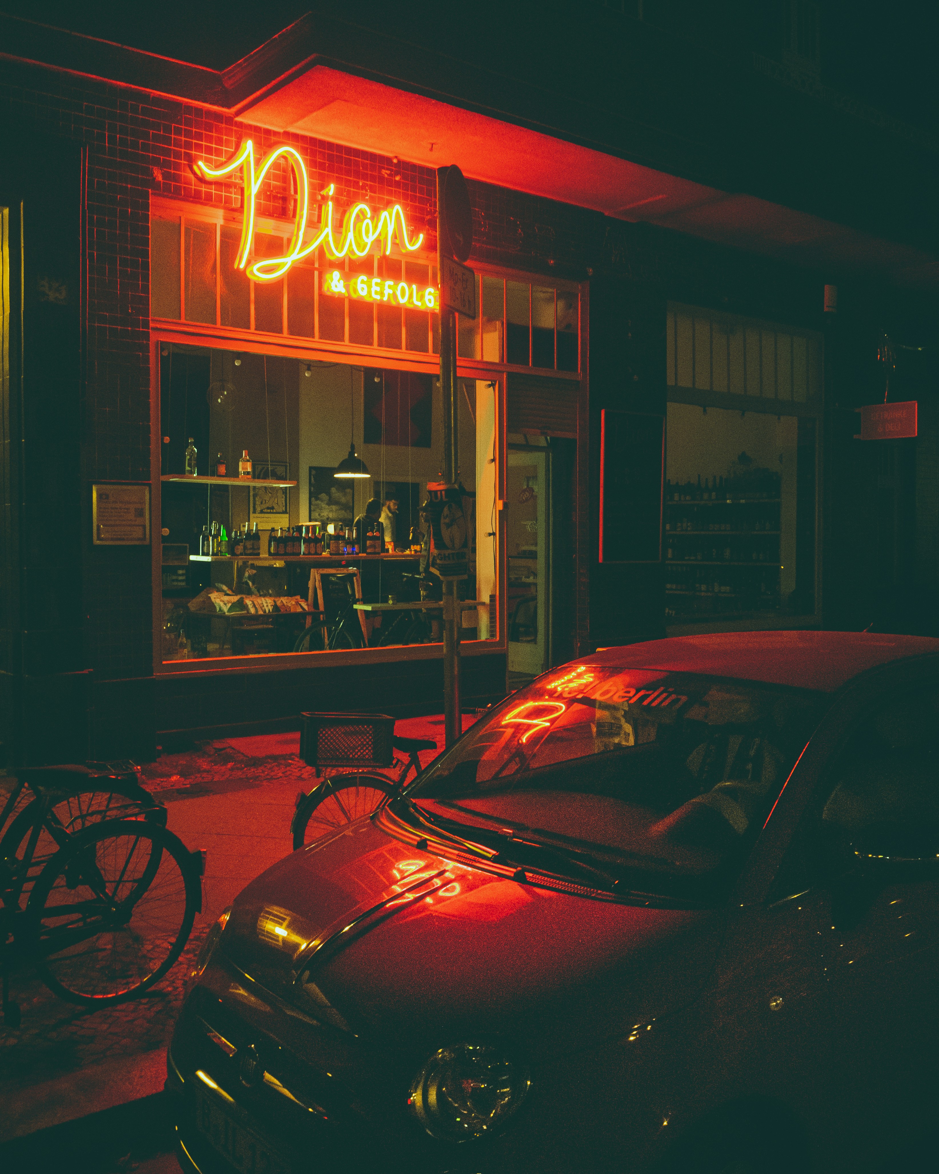 Neon Sign Over a Quiet Night: Amber Reflections on a Red Car