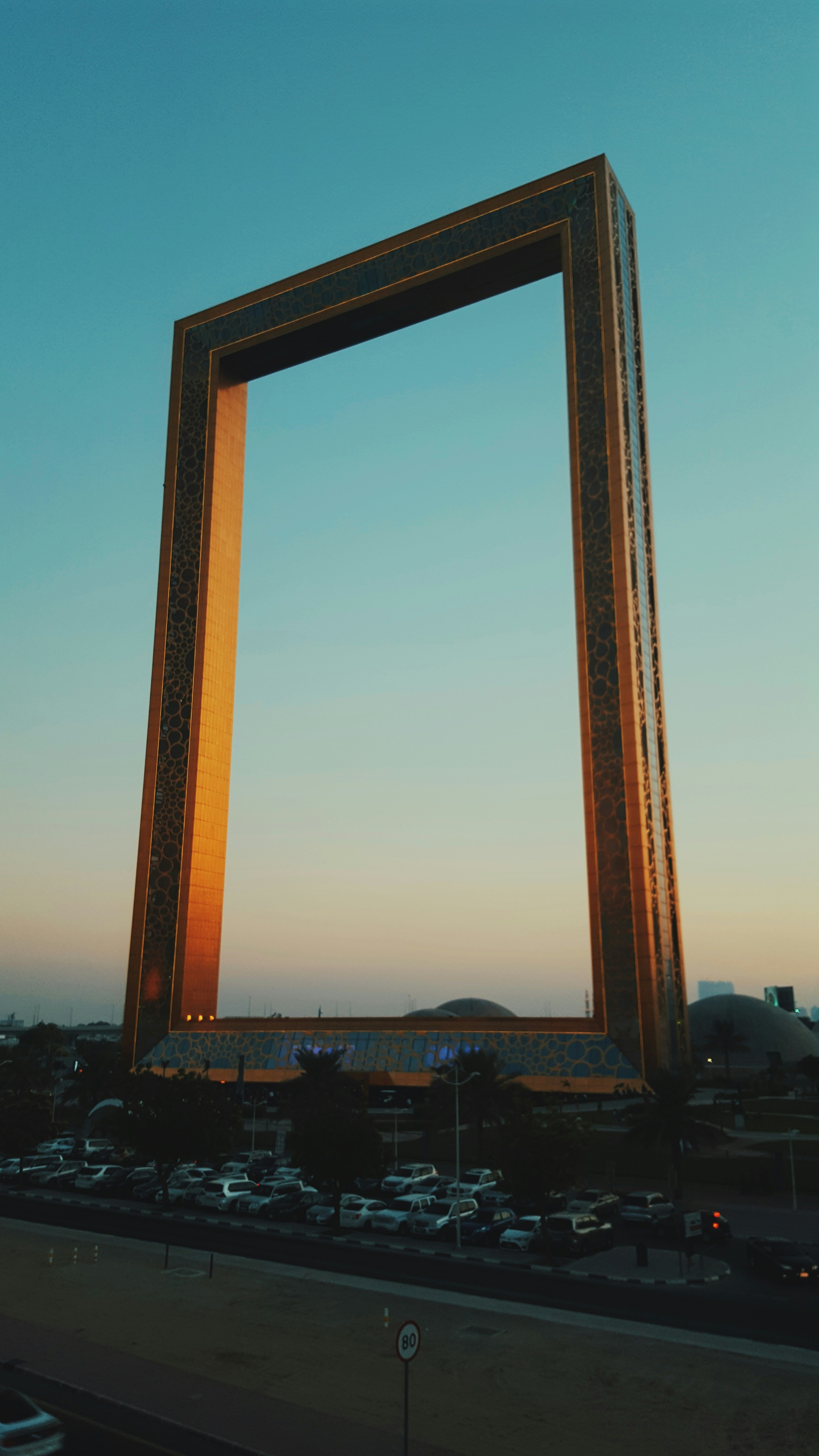 Iconic architectural structure framed by a gradient twilight sky, highlighting its golden hues. The scene captures the essence of modern design in urban landscapes.