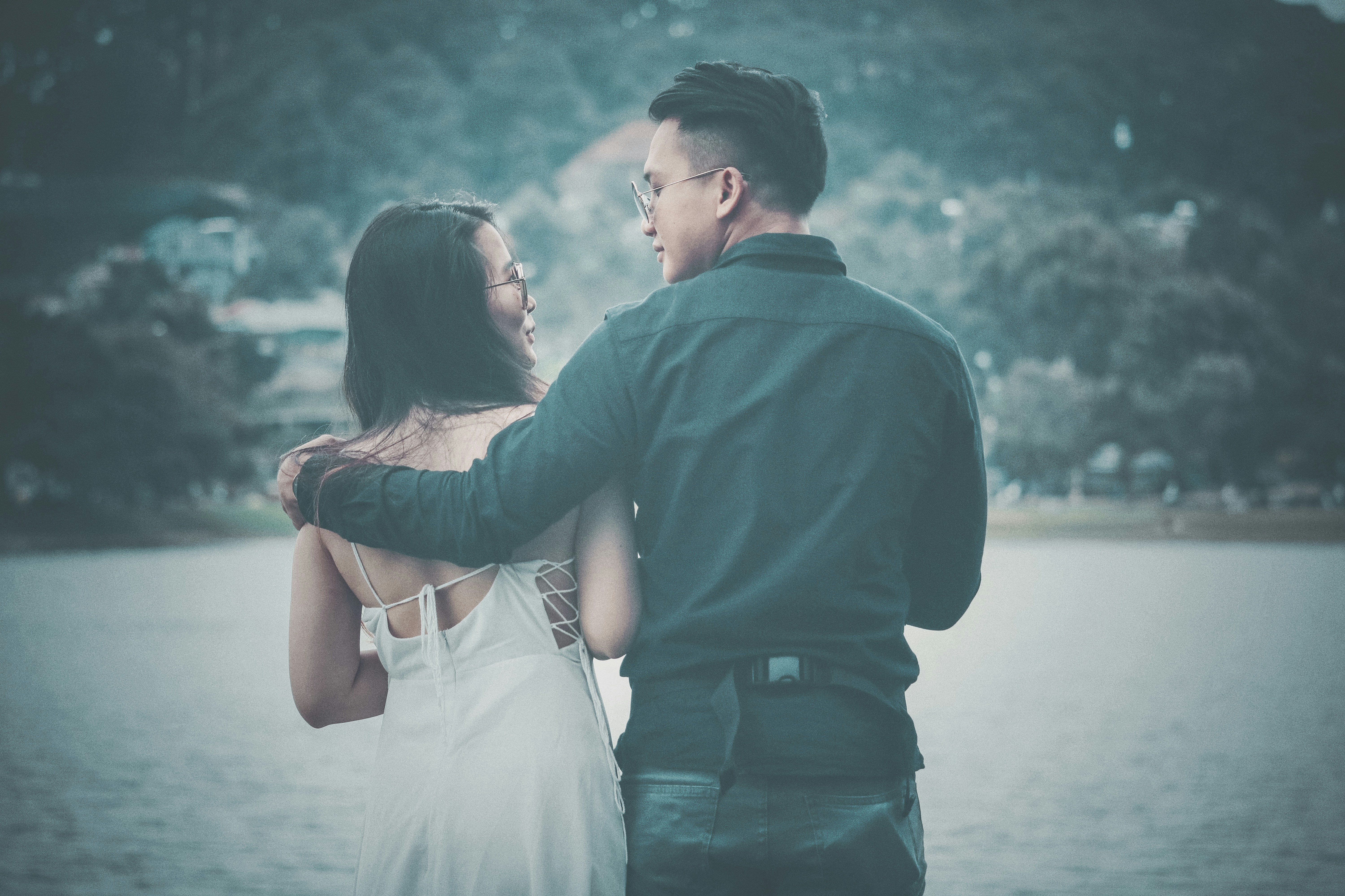 man and woman facing on body of water