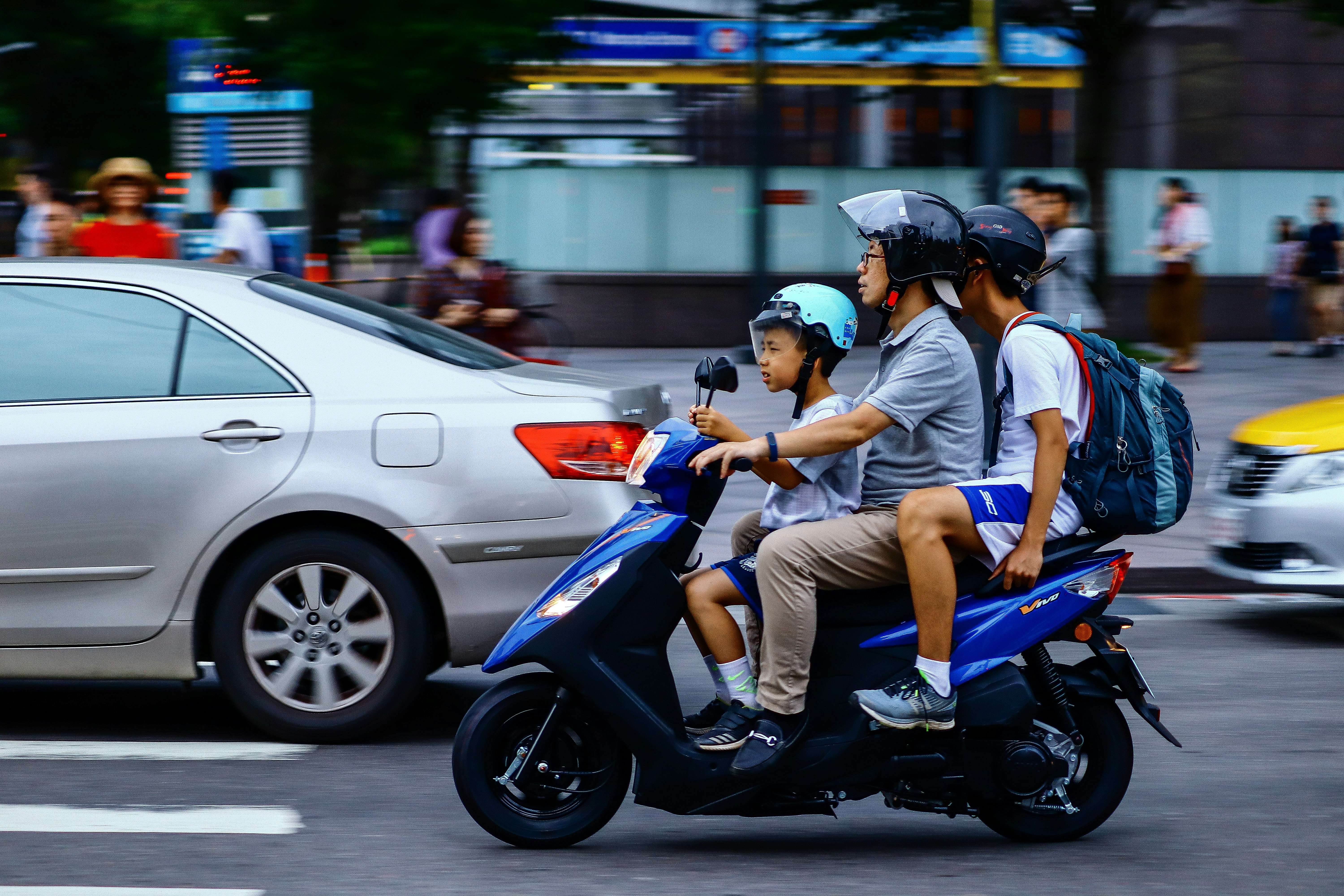 three people riding blue motor scooterSamuel Toh