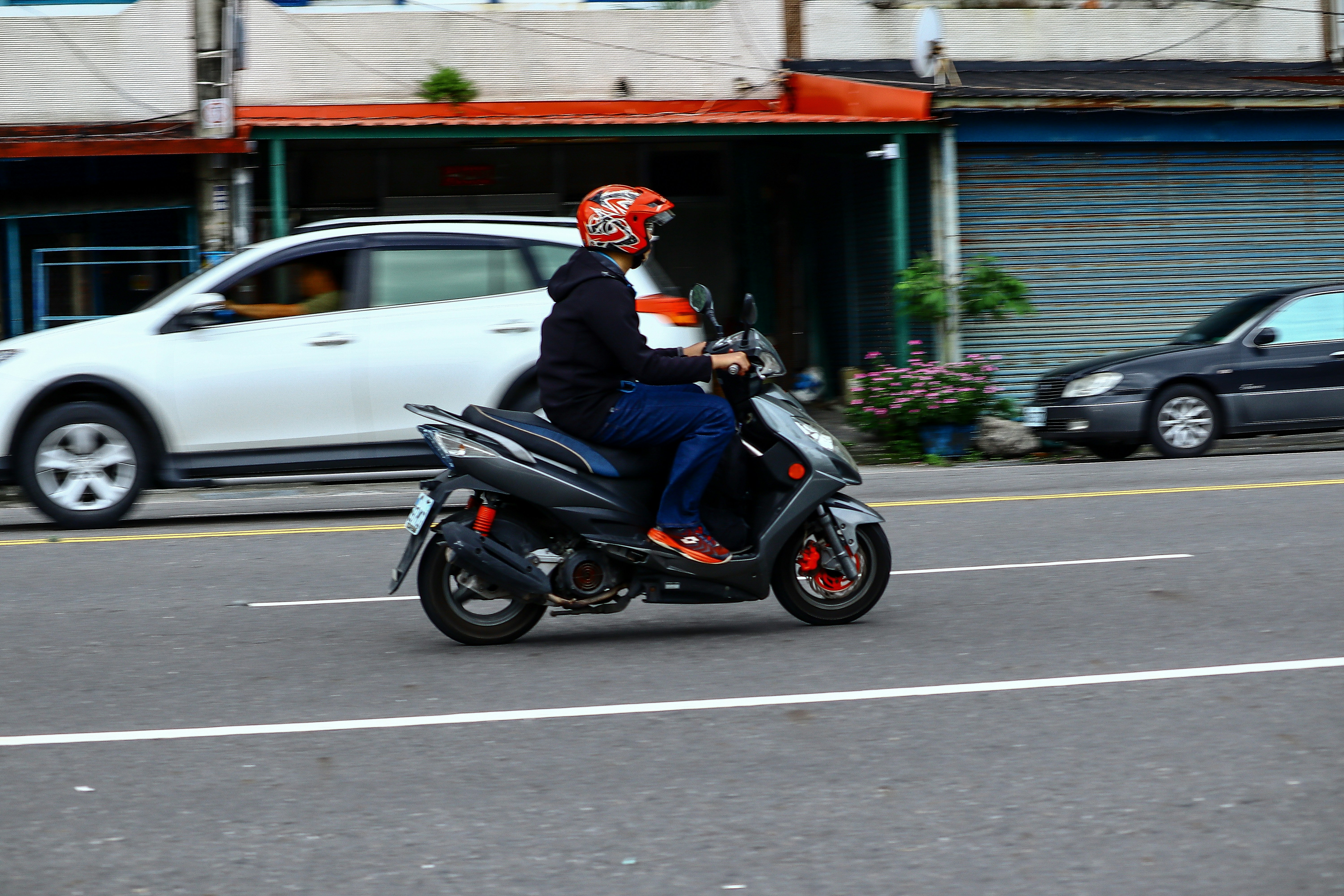 A rider in a vibrant helmet navigates a city street on a sleek scooter, capturing the essence of urban mobility.