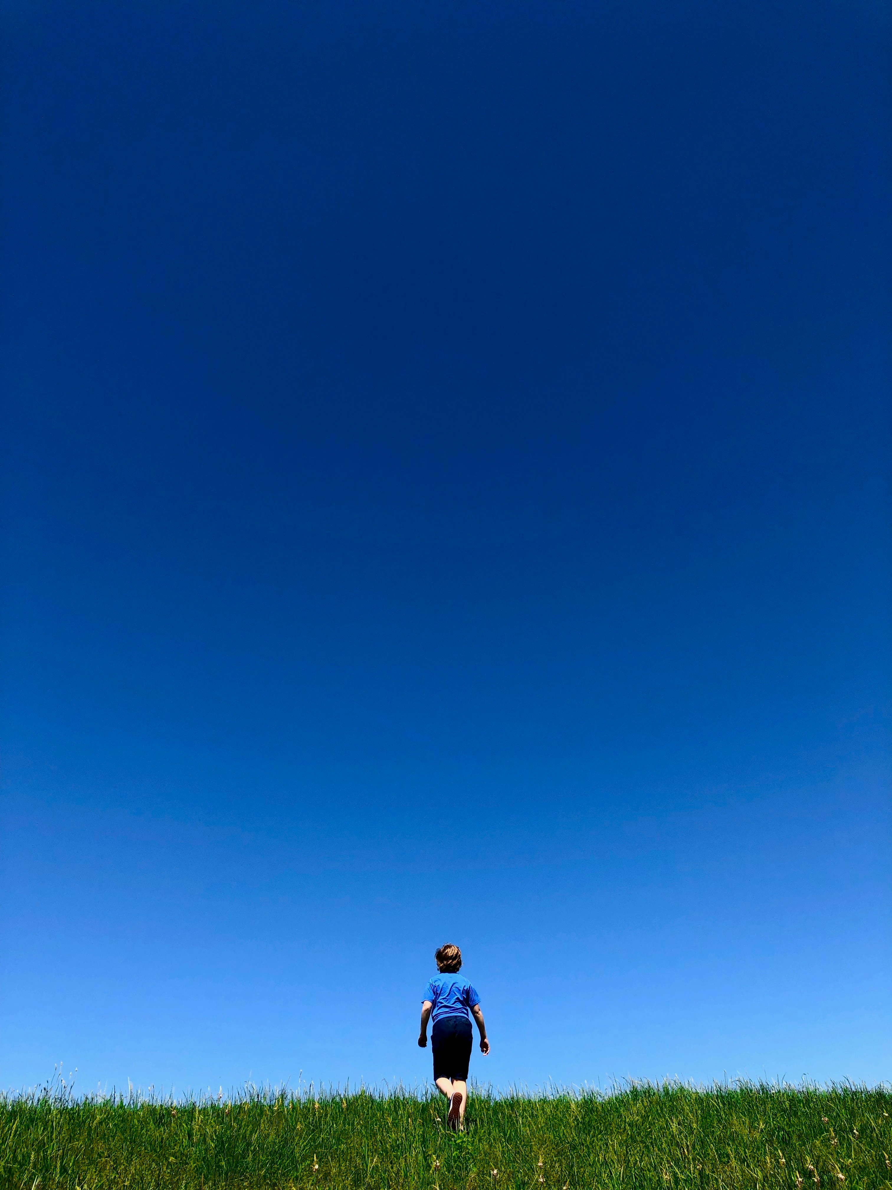 man in blue t-shirt and black shorts walking in green grass field