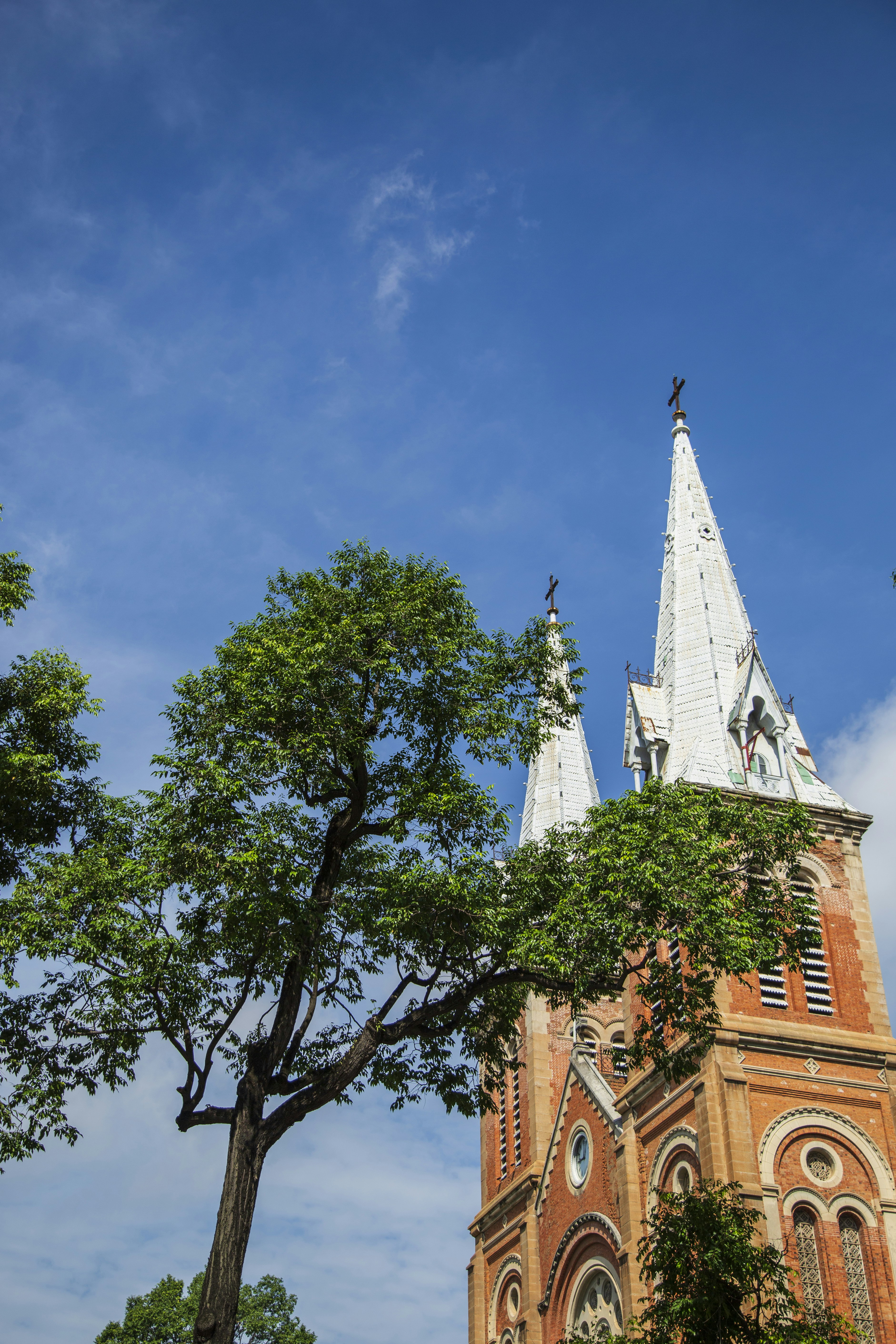 Historic church with tall, pointed towers surrounded by lush greenery under a clear blue sky.