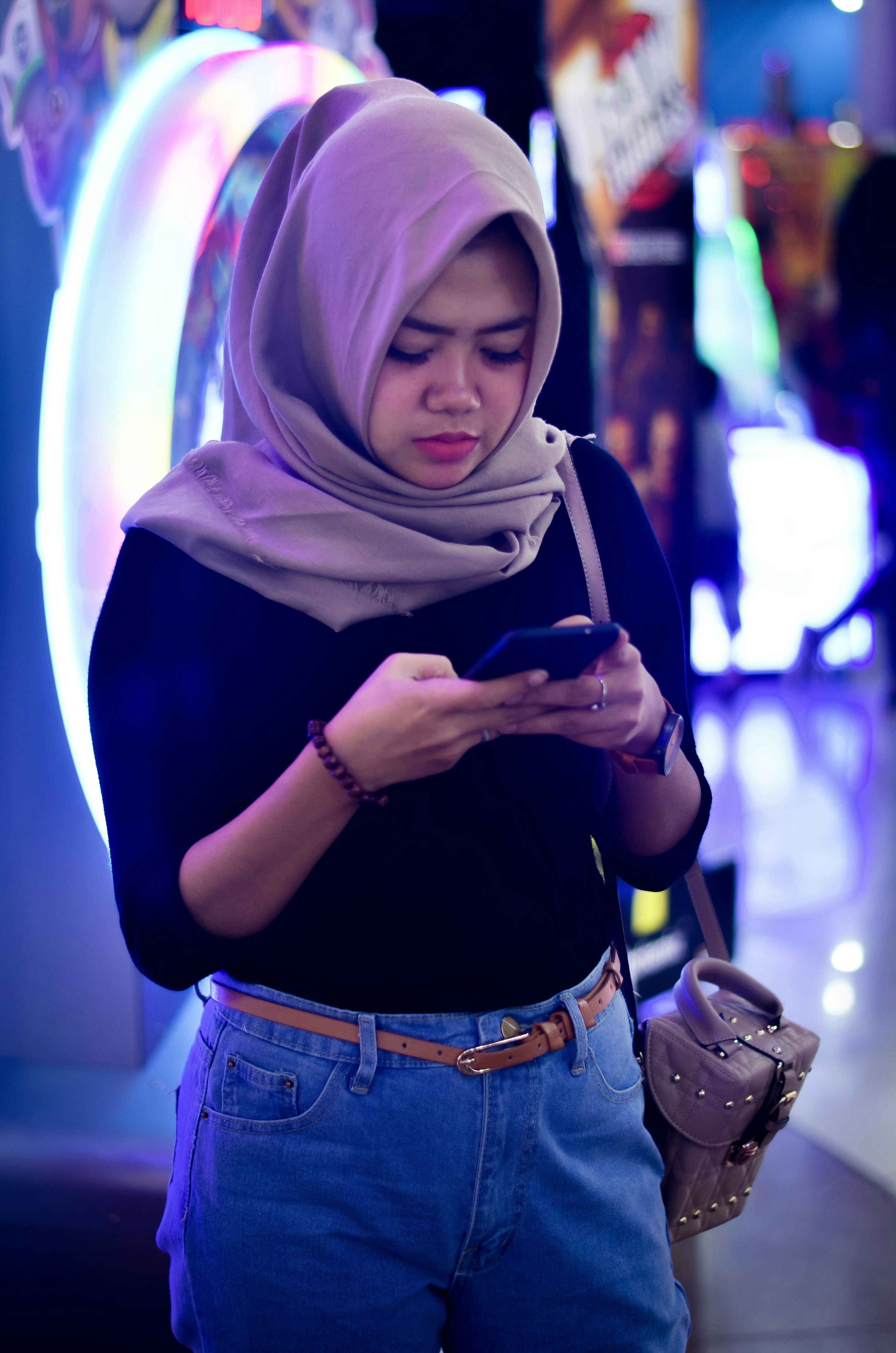 Neon Quiet in the Arcade: Focused Moment Beneath Iridescent Glow