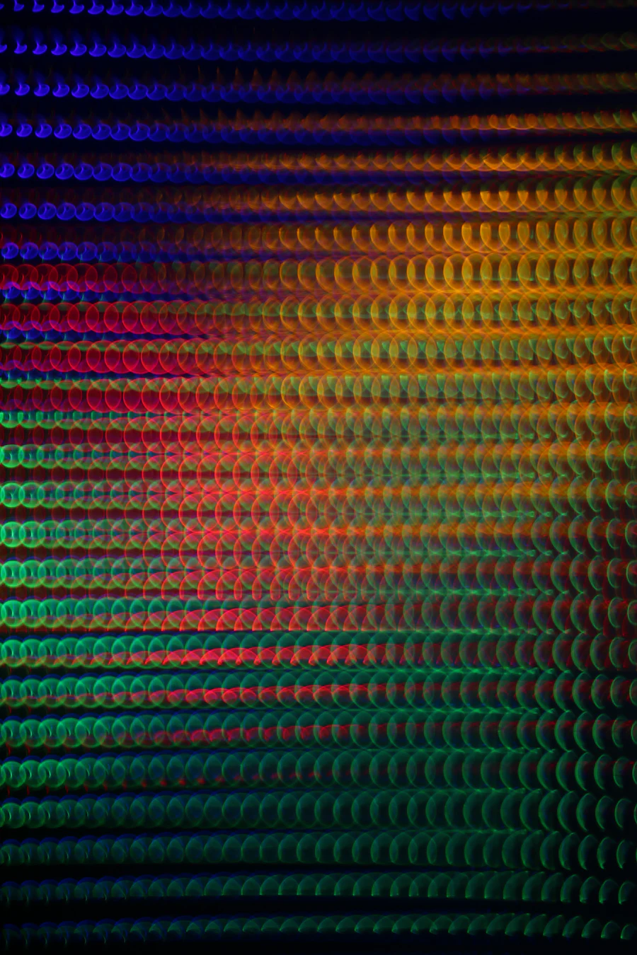 Abstract pattern of overlapping neon circles and horizontal bands shifting from blue and magenta to orange and green. Dark gaps create a moody, textured backdrop.