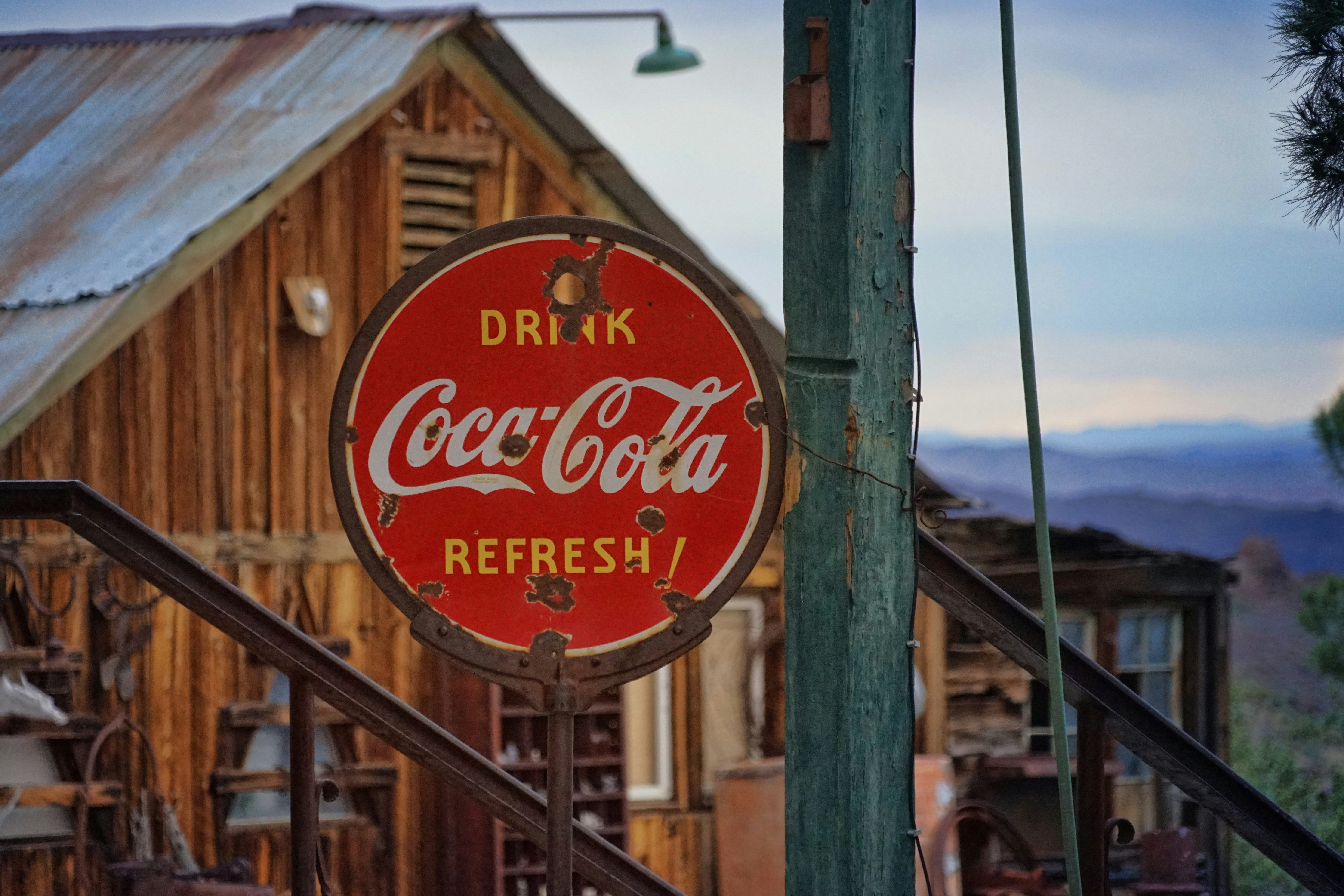 Weathered Coca-Cola sign mounted on a rustic wooden building, evoking a sense of vintage charm and nostalgia.