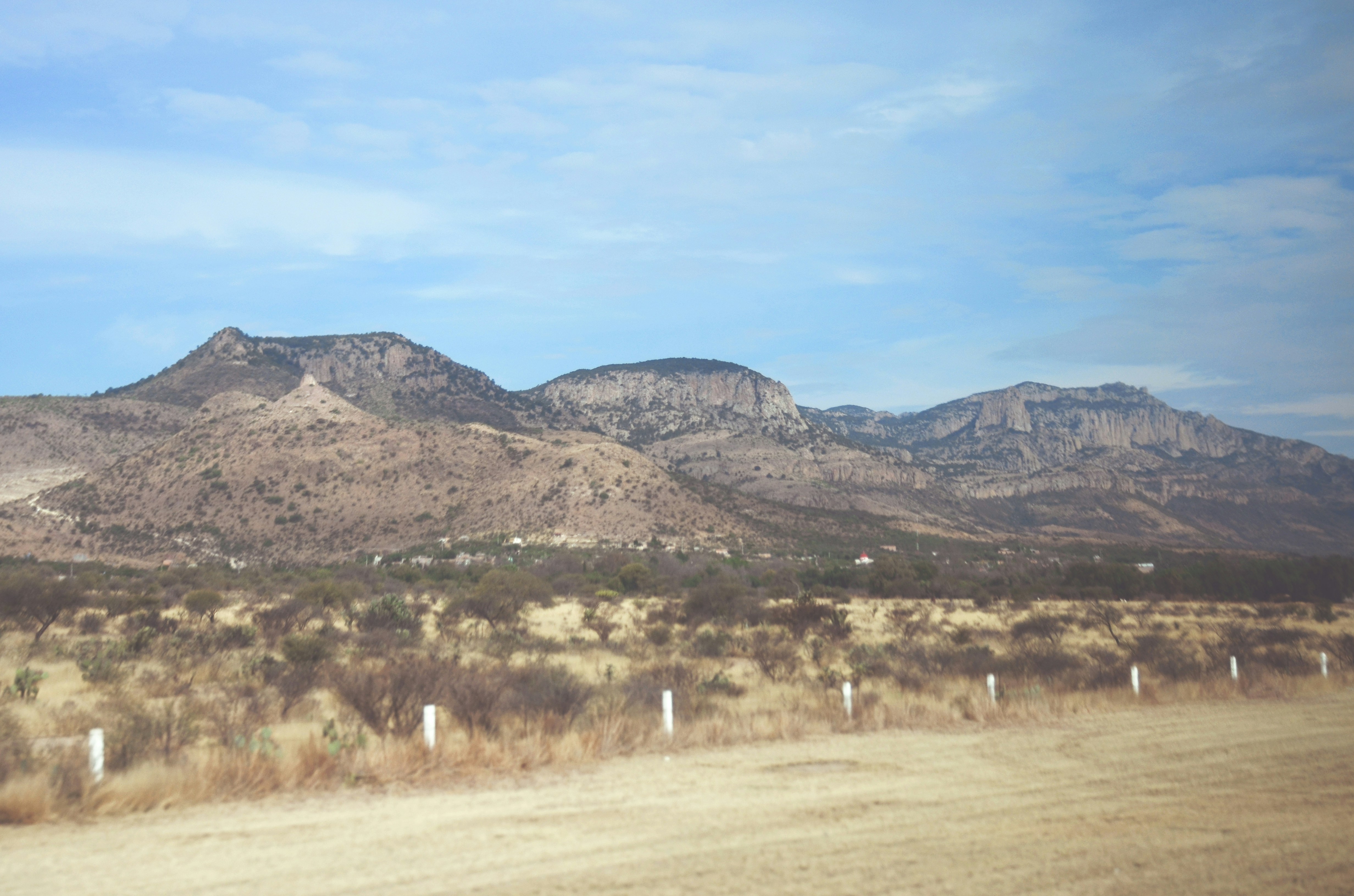 Vast desert landscape featuring rugged mountains under a clear blue sky, showcasing the natural beauty of the terrain.