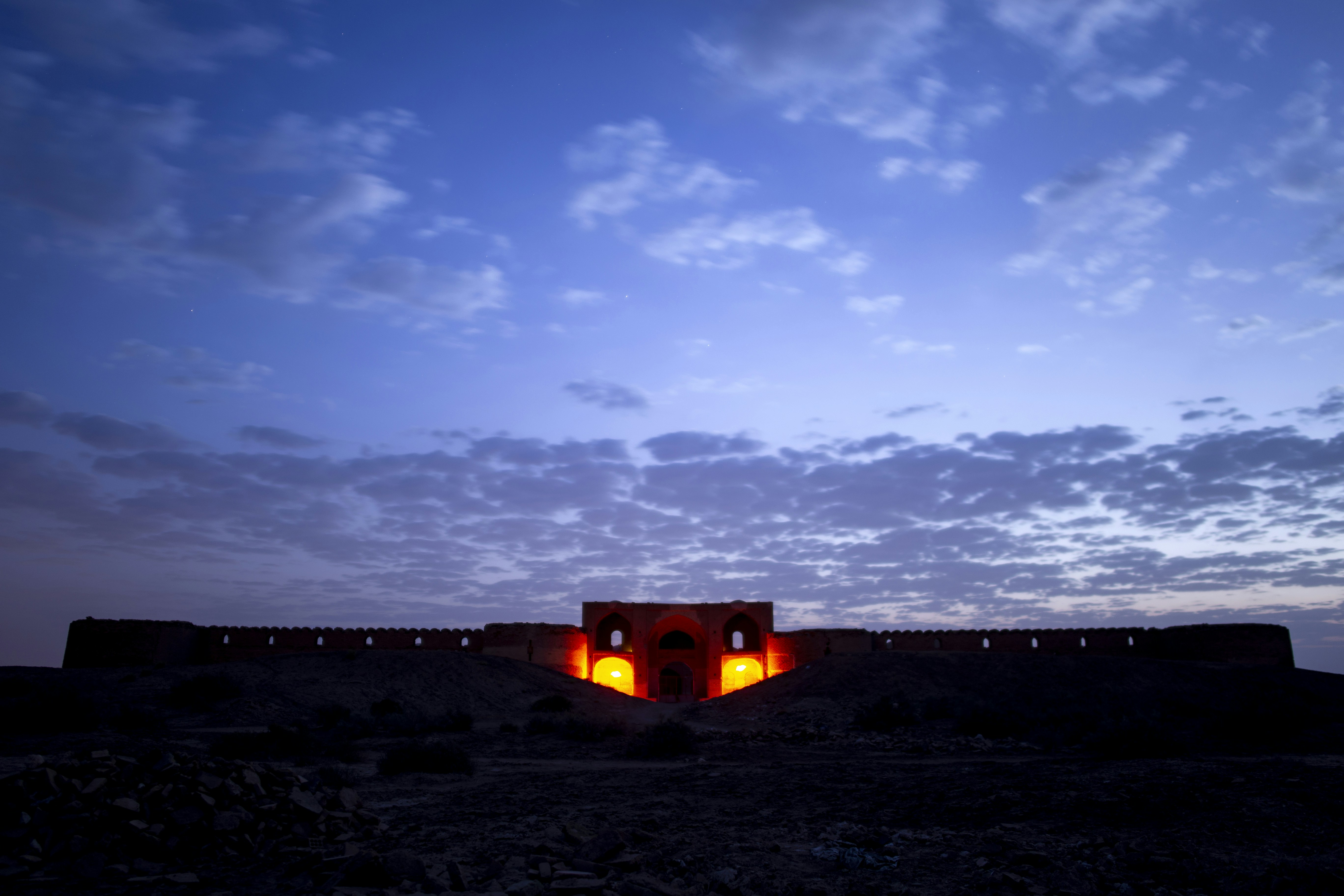 Ember-Glow Gatehouse at Dusk, a Fortress Silhouette Against a Velvet Blue Sky