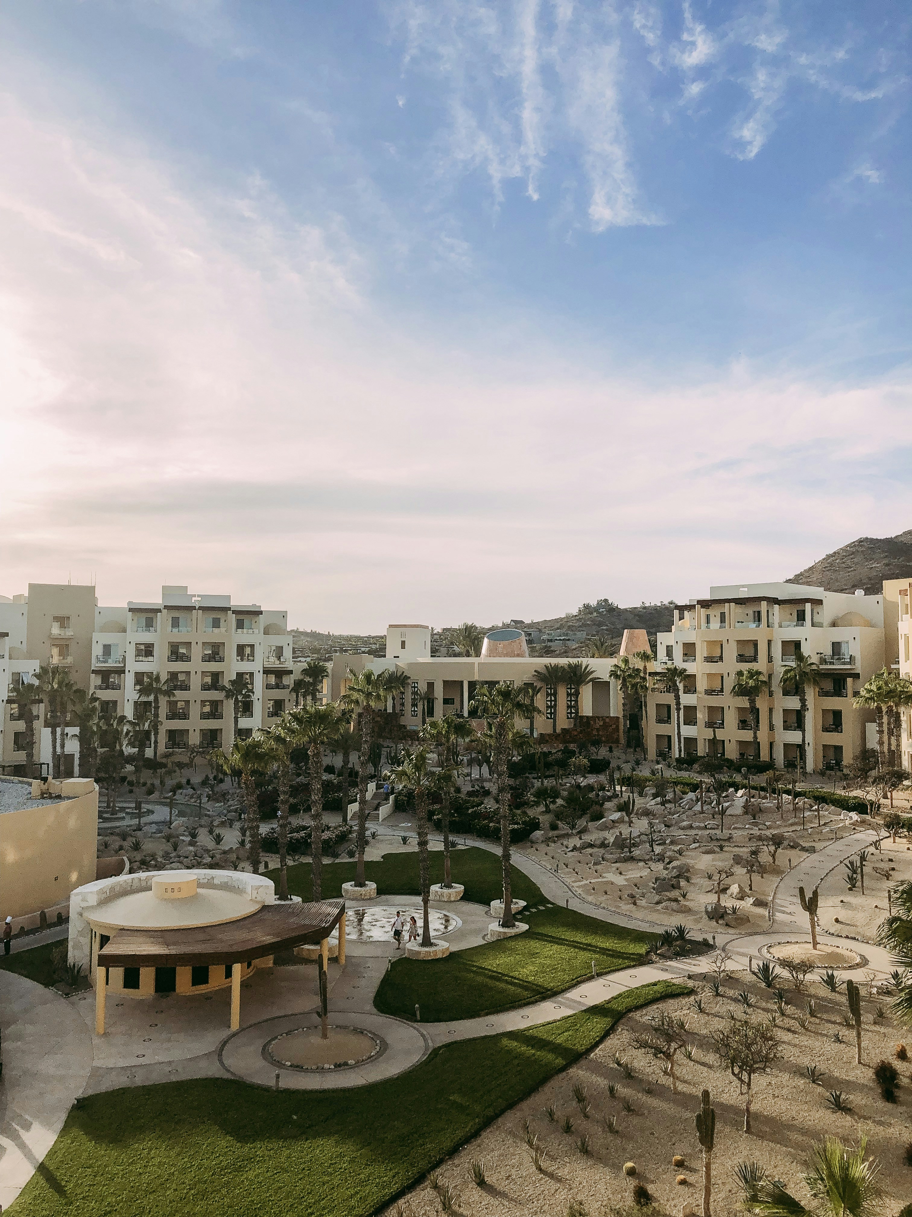 Expansive resort view with sandy pathways and lush greenery under a pastel sky.