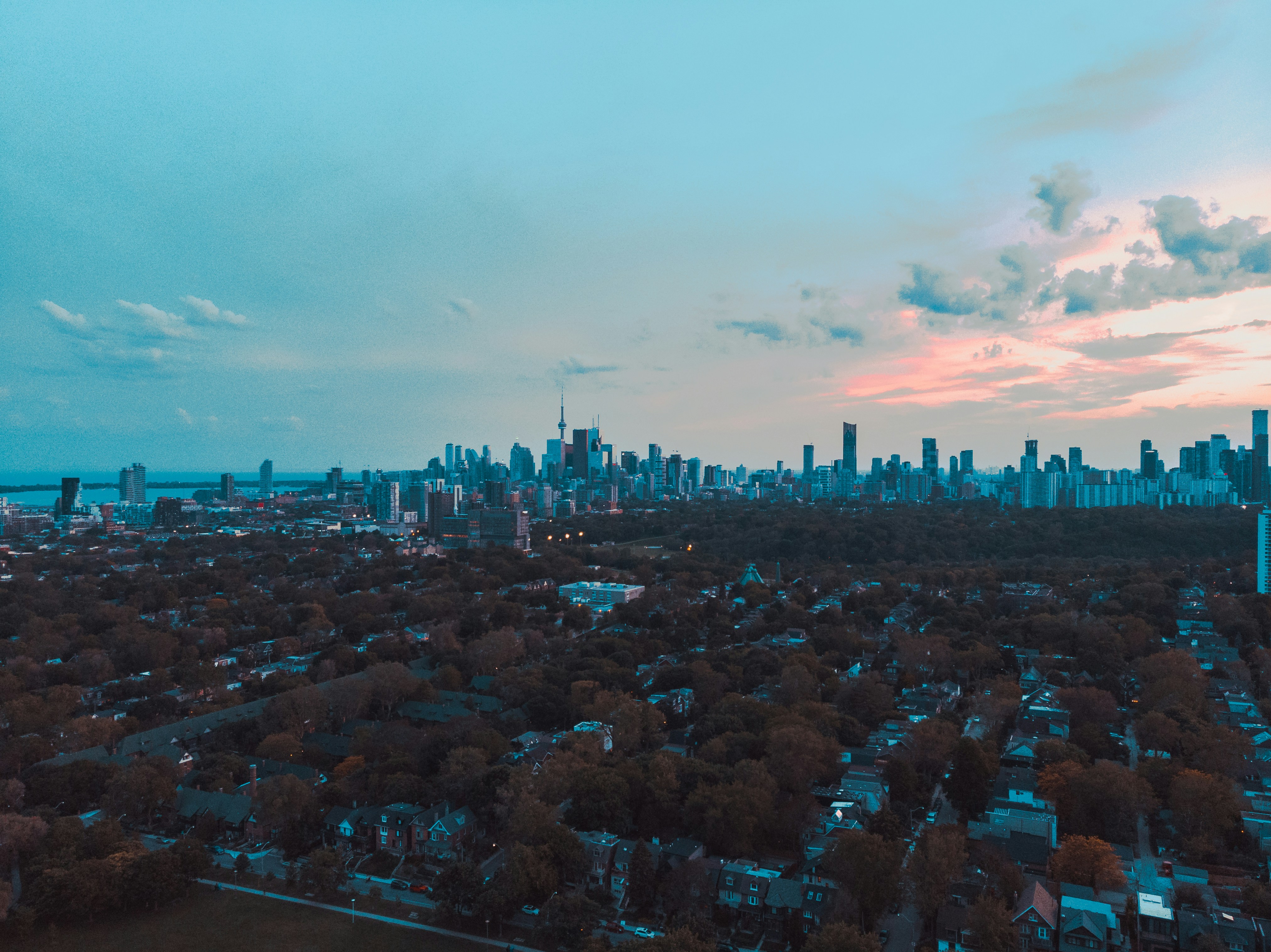 City skyline silhouetted against a vibrant sunset sky with scattered clouds.