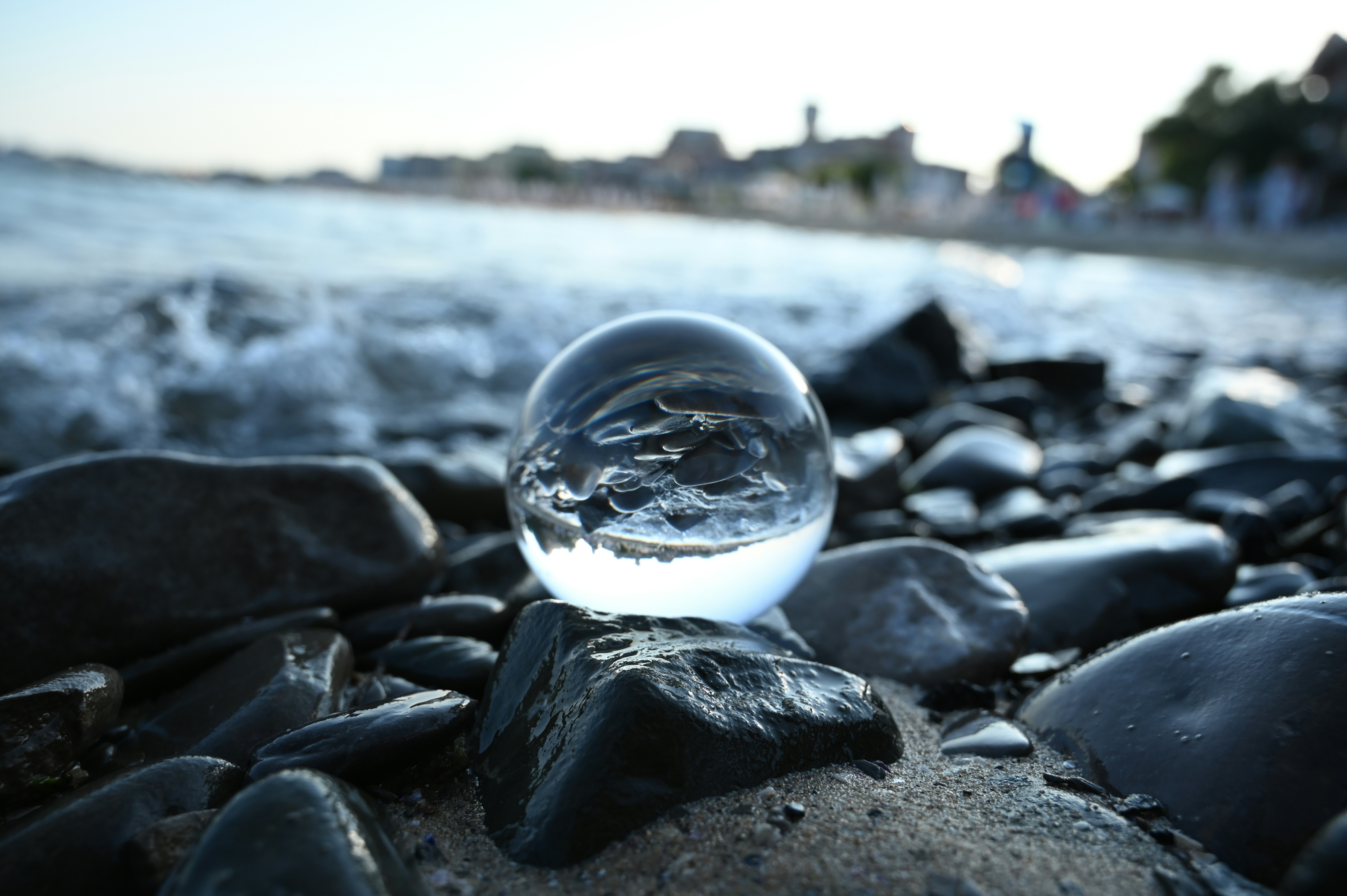 Glass Sphere on Pebbled Shore: A Moment of Coastal Quiet