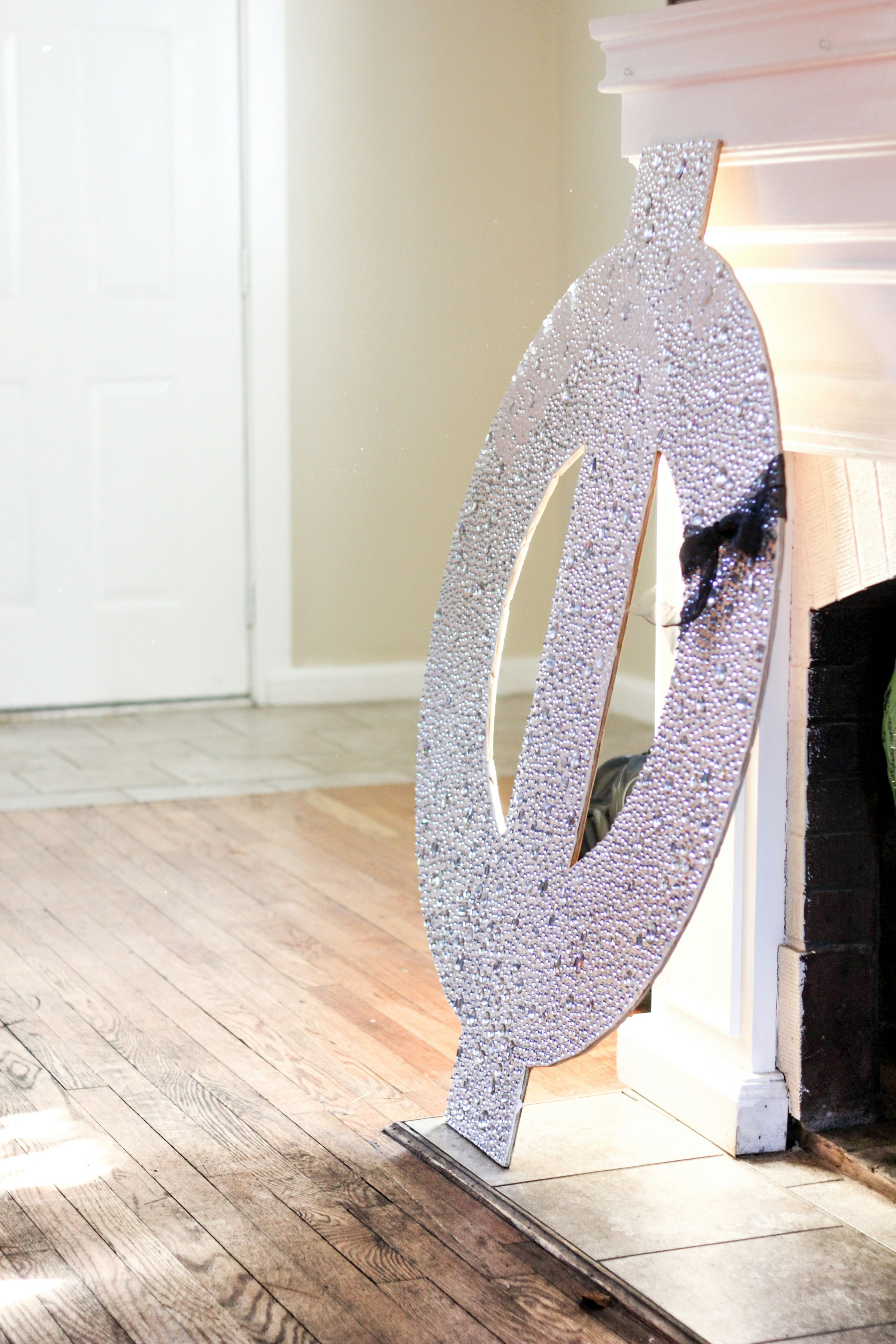 A large, sparkling letter 'O' stands against a fireplace, reflecting light and adding a whimsical touch to the room's decor.