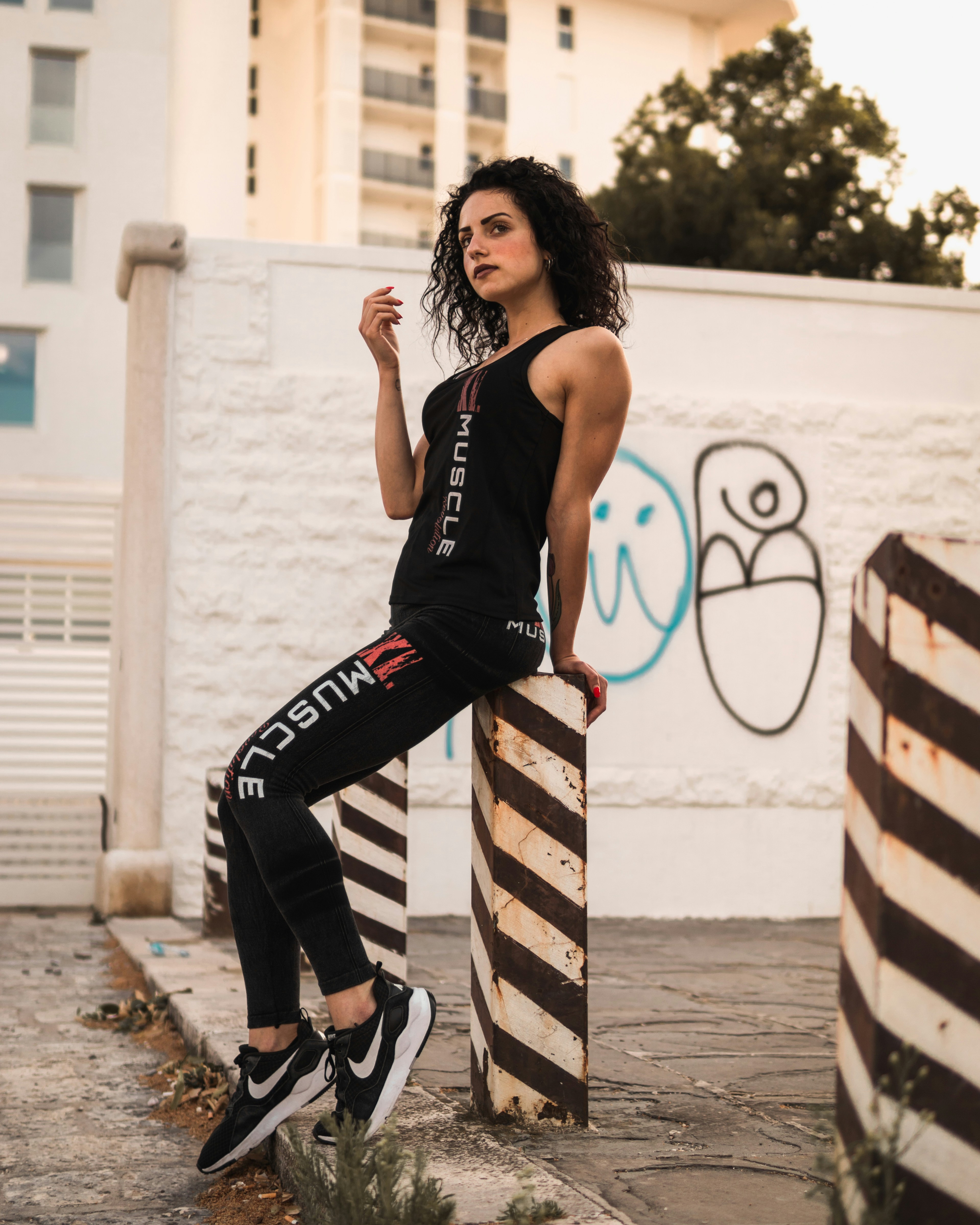 woman wearing black tank top sitting on concrete post