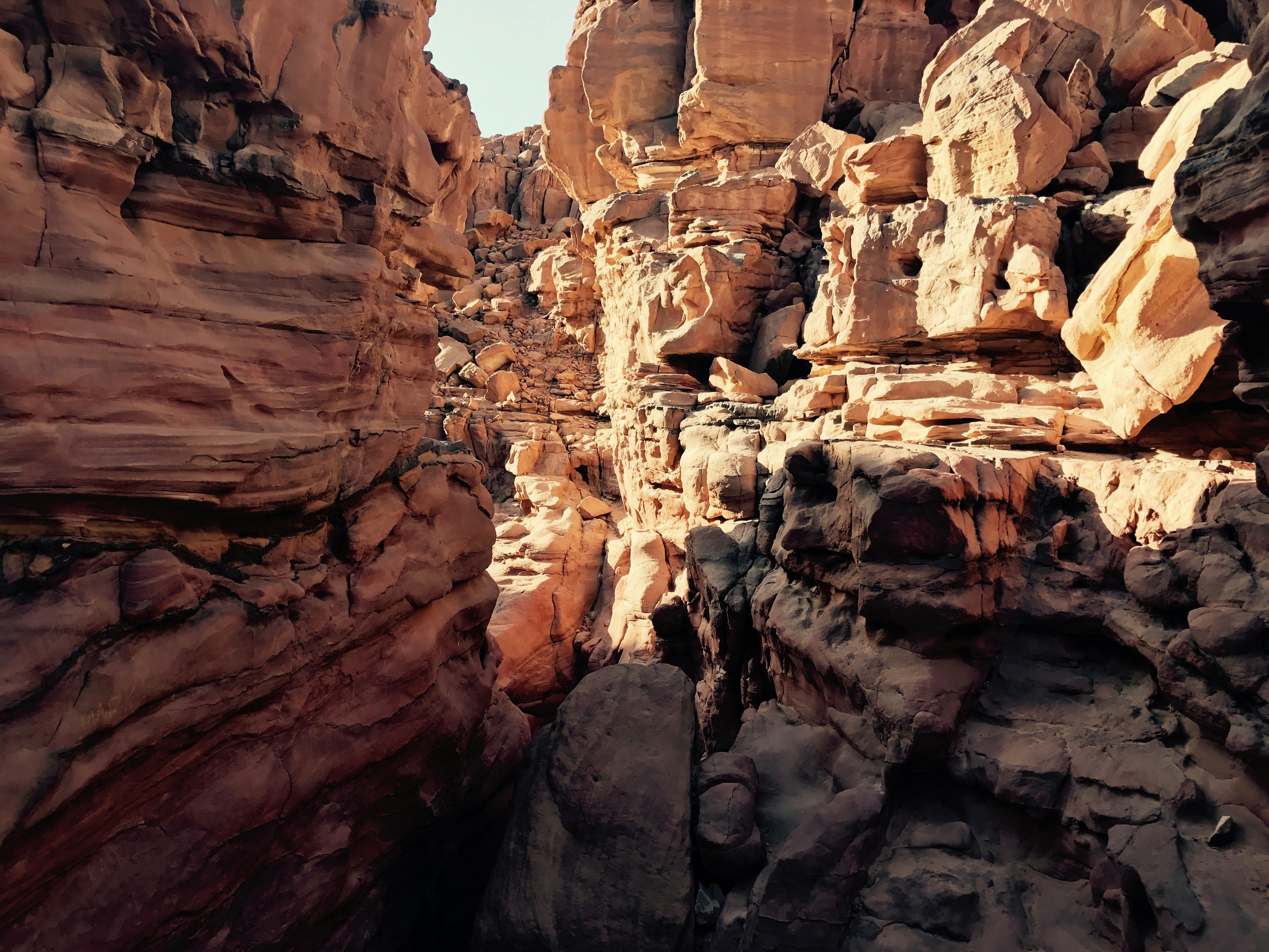 Sunlit rock formations with rugged textures and deep shadows in a canyon.