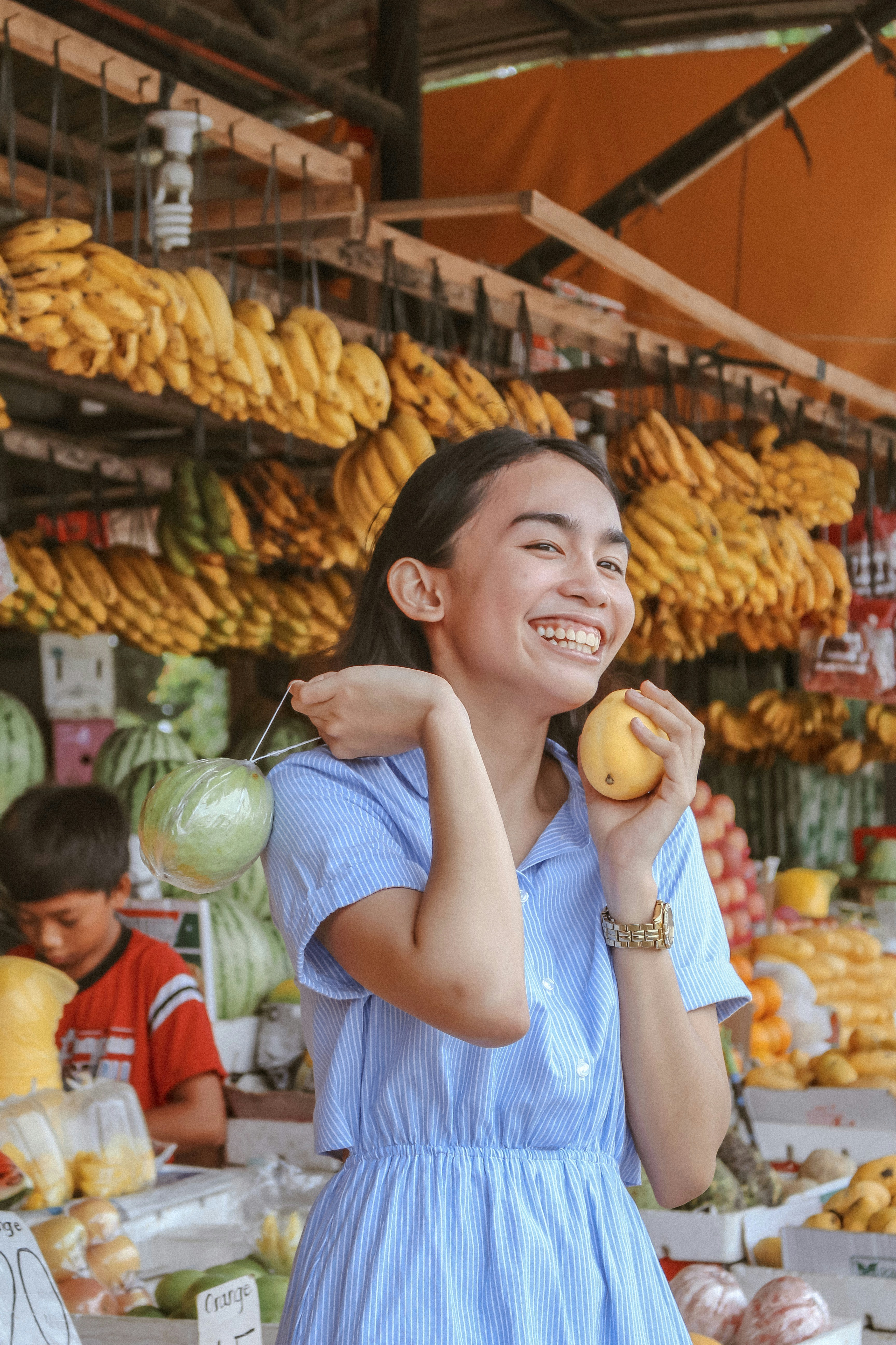 Bright Smile Amid Hanging Bananas: A Market Moment