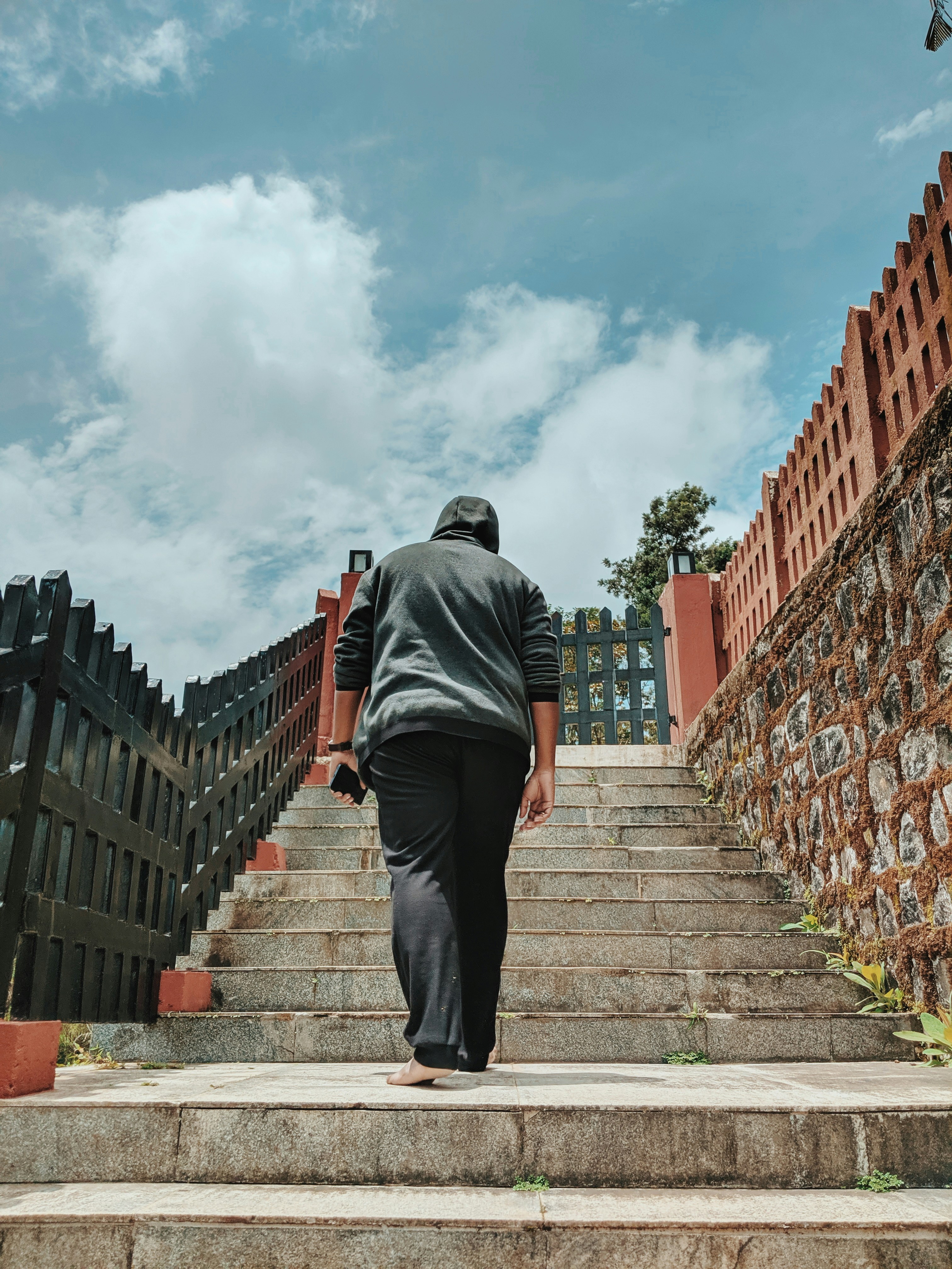 Climber in Hoodie: Ascending a Staircase to Open Sky