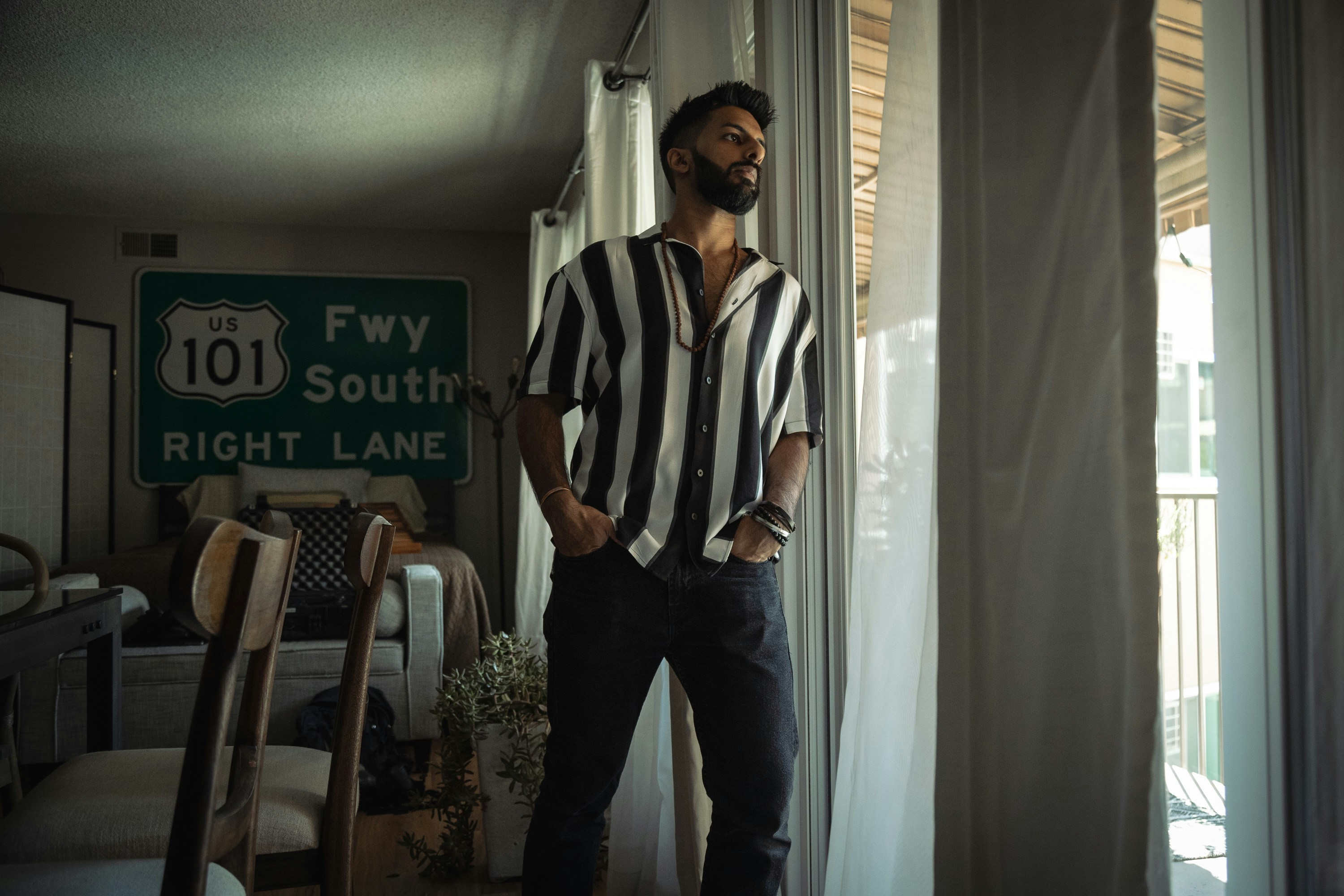 Sunlit Contemplation by the Window: Striped Portrait with a Highway Backdrop
