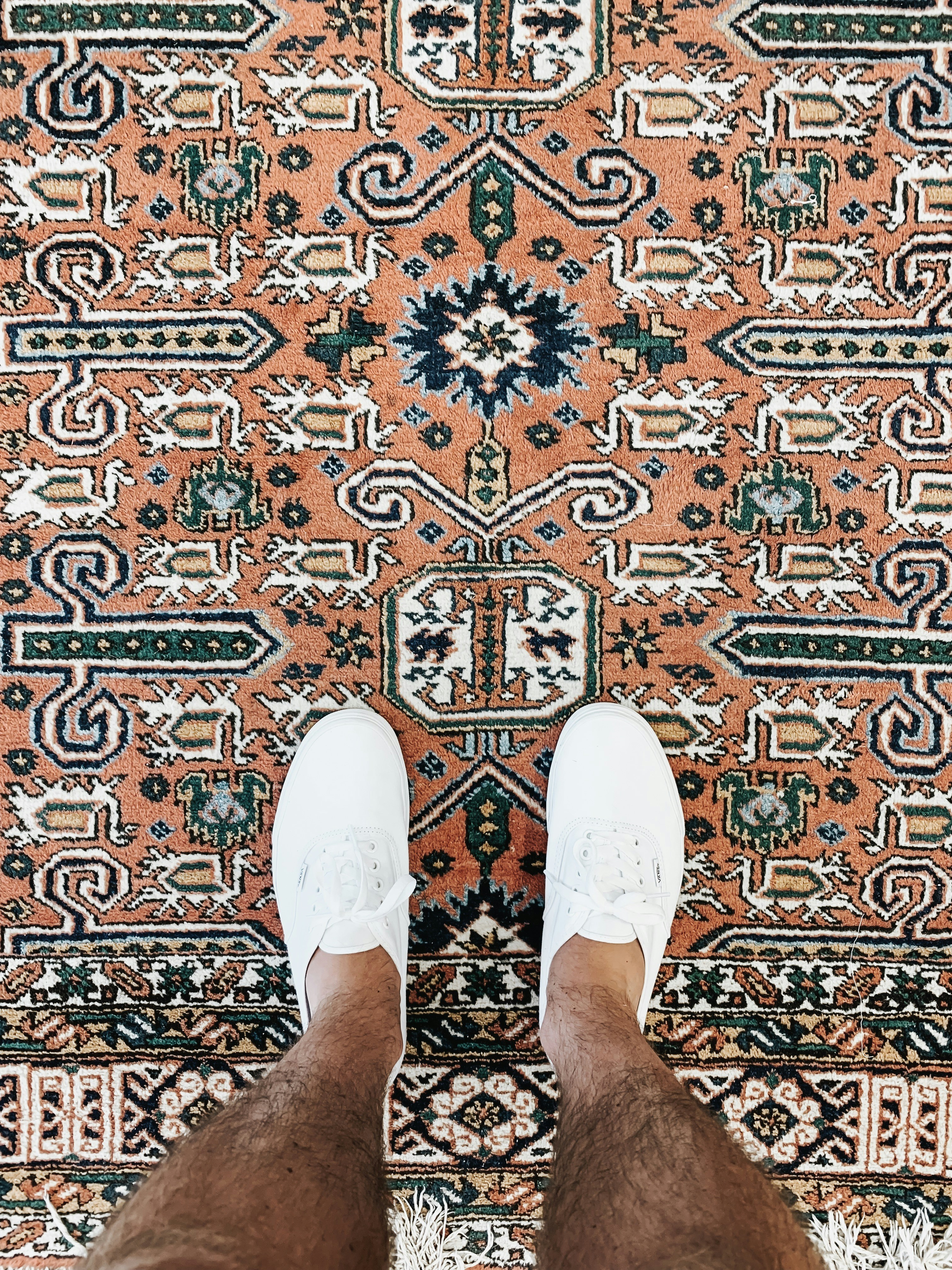 Footsteps on a Persian-inspired rug: white sneakers anchor a maze of pattern.