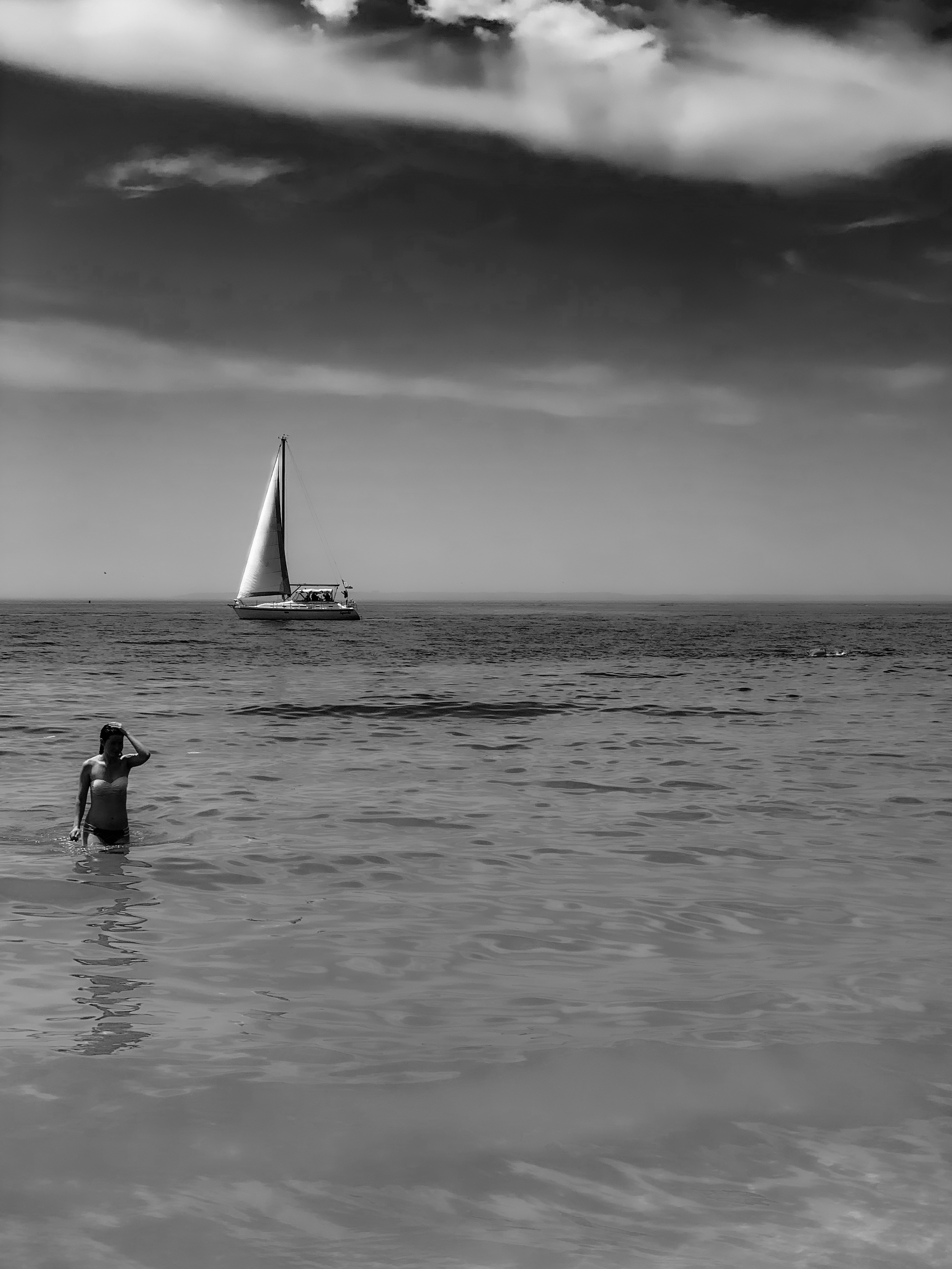 Tidebound Solitude: A Lone Swimmer and a Distant Sail on Quiet Seas