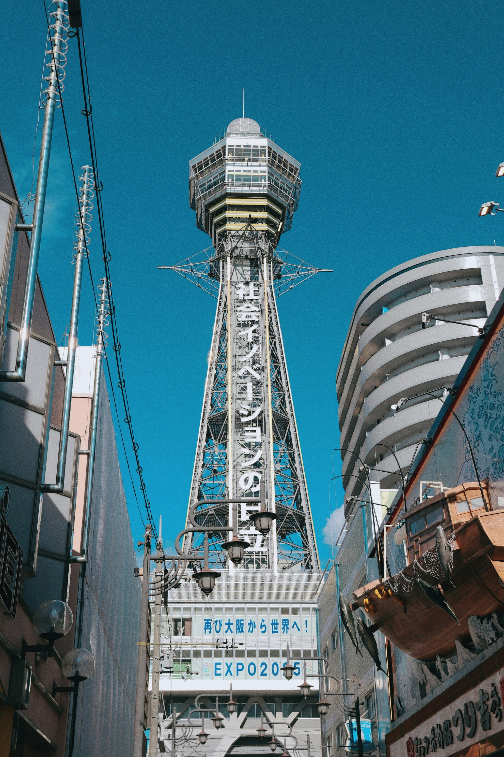Iconic observation tower framed by urban structures, showcasing a blend of modern architecture and vibrant signage.