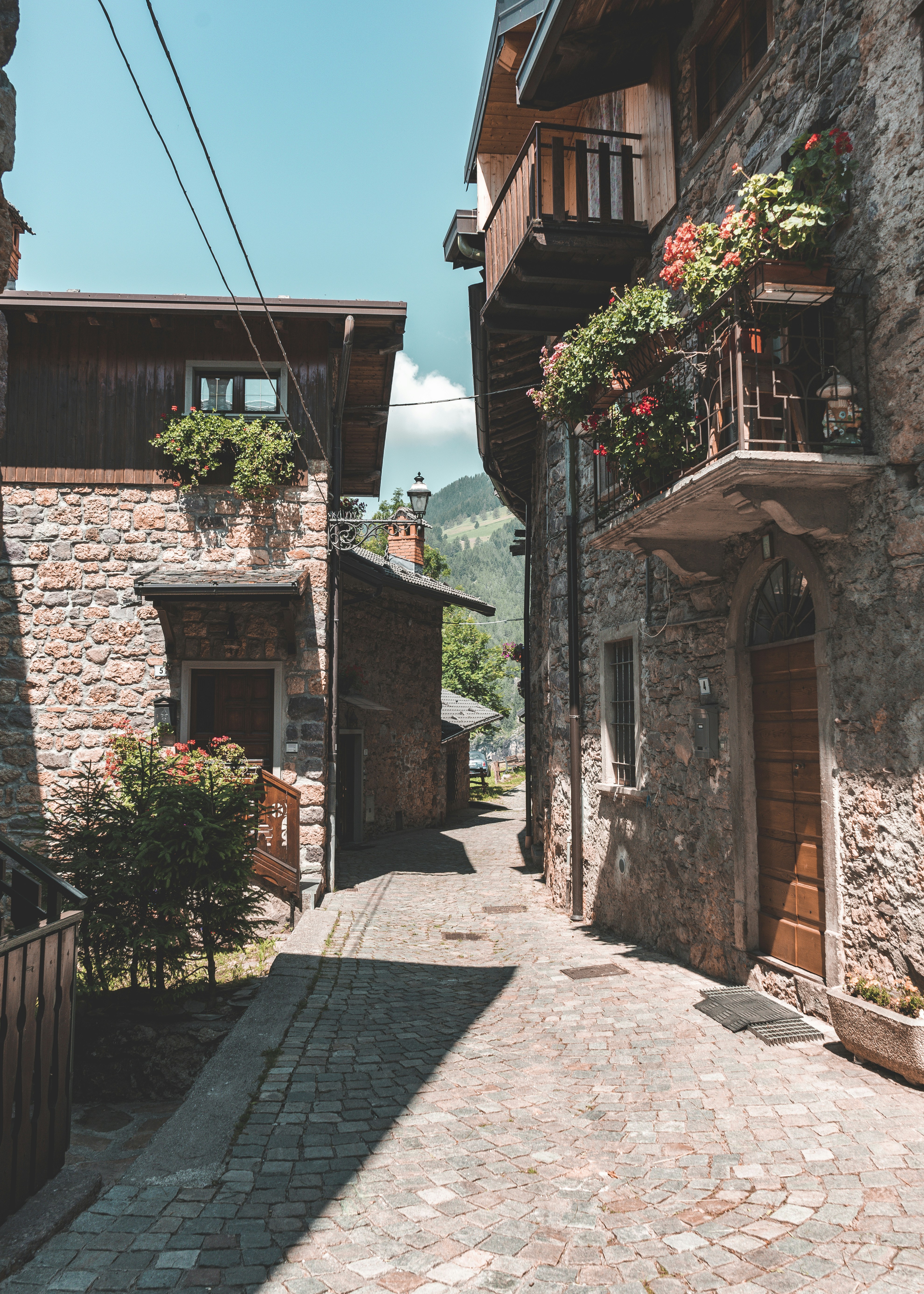 Sunlit Alpine Alleyway Framed by Weathered Stone Balconies