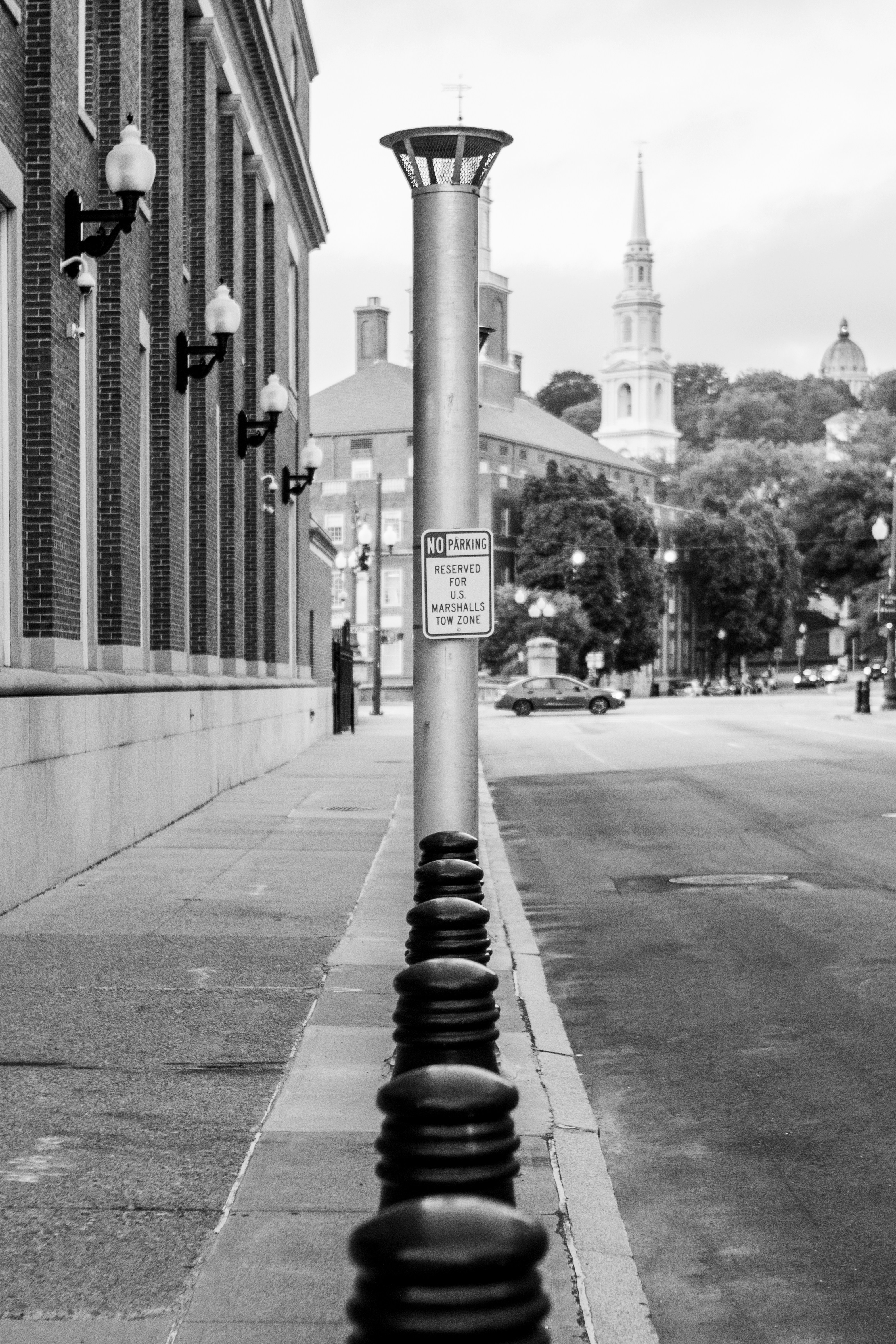 Pole and Bollards: A Monochrome Urban Corridor with a Distant Spire
