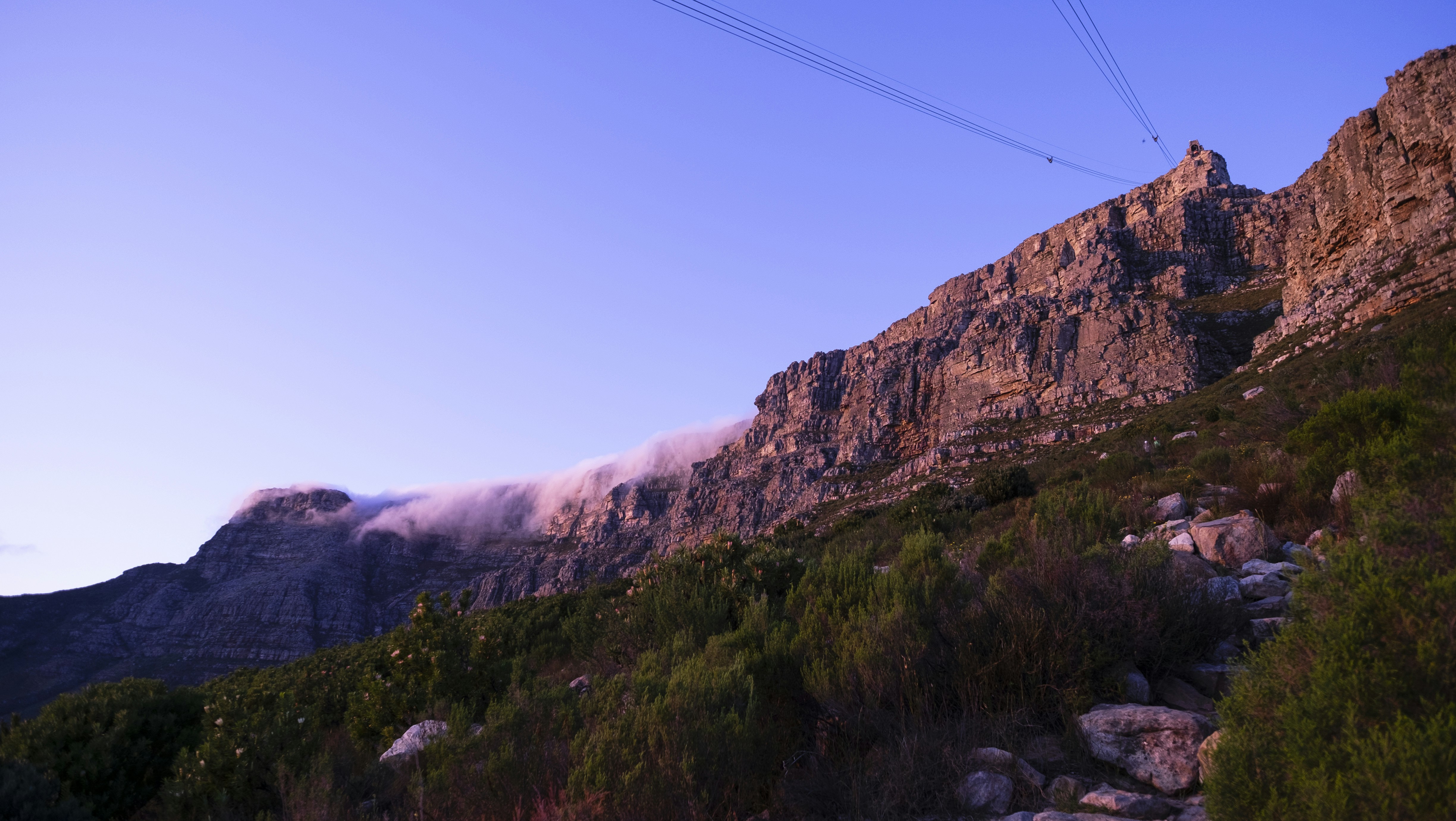 Table Mountain draped in mist under a gentle sunrise with vibrant purple hues.