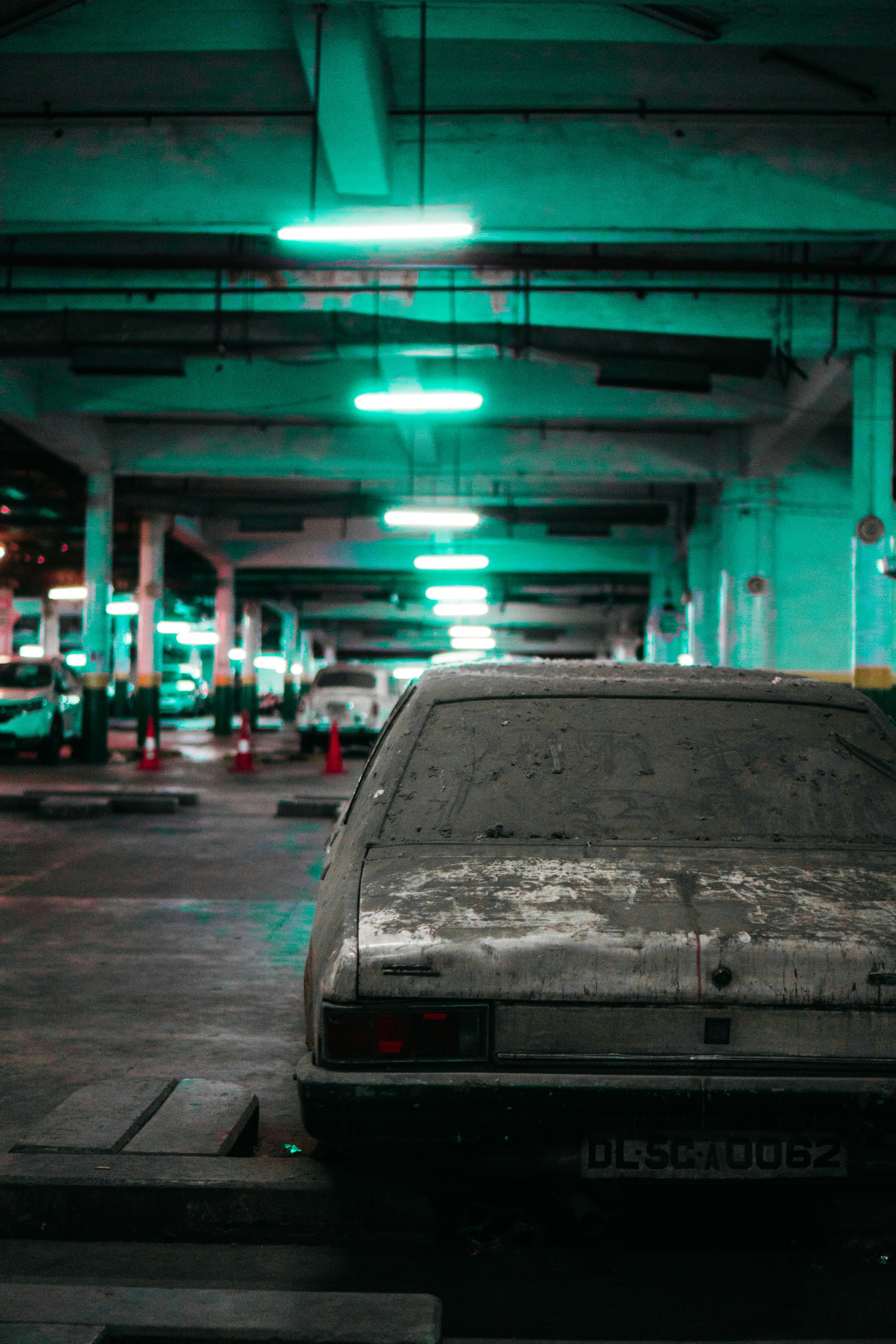 Neon-Lit Relic: Dusty Sedan in a Teal Underground Parking Garage