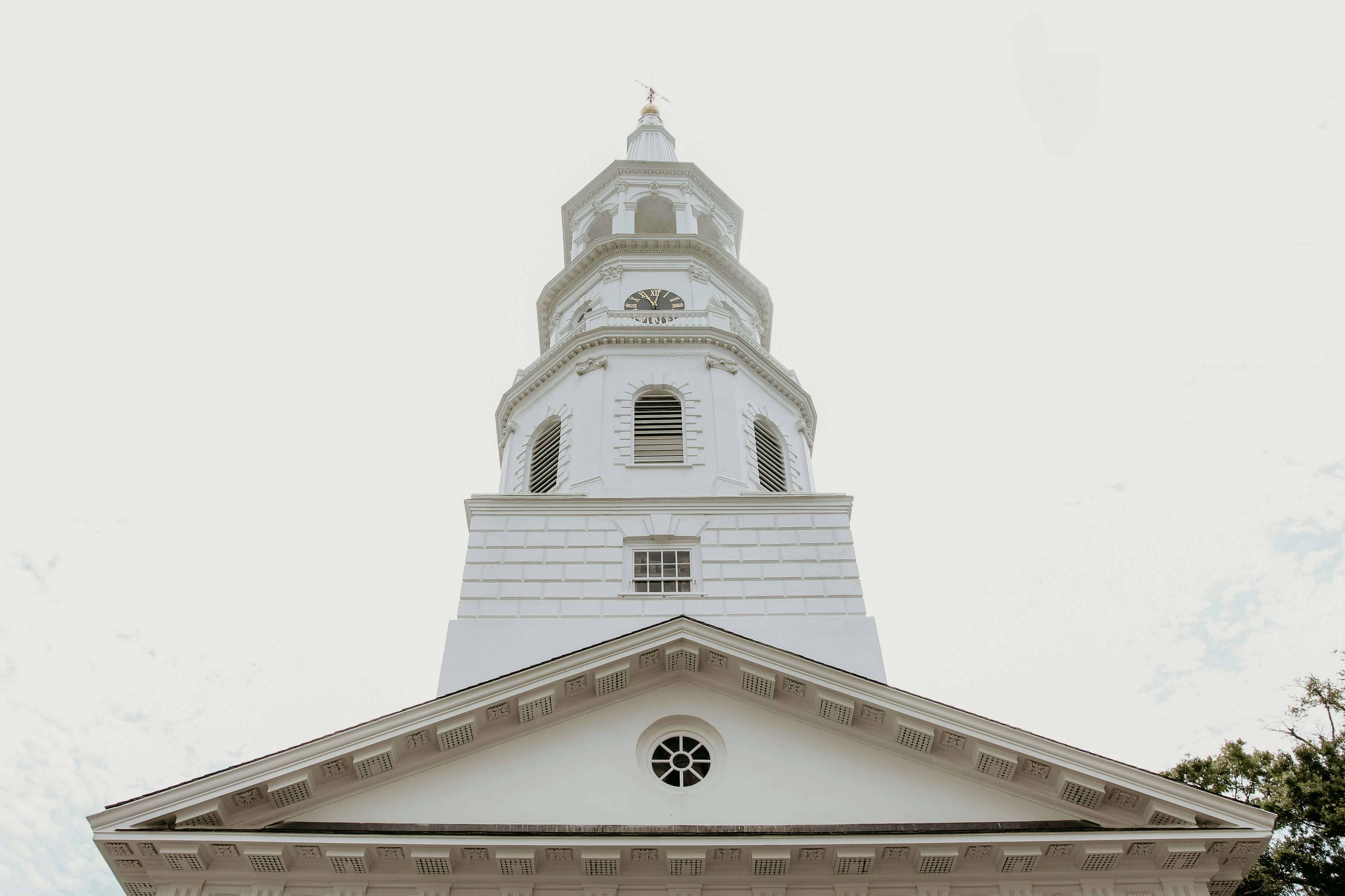 White church tower rising against a bright sky, showcasing symmetrical architectural details.