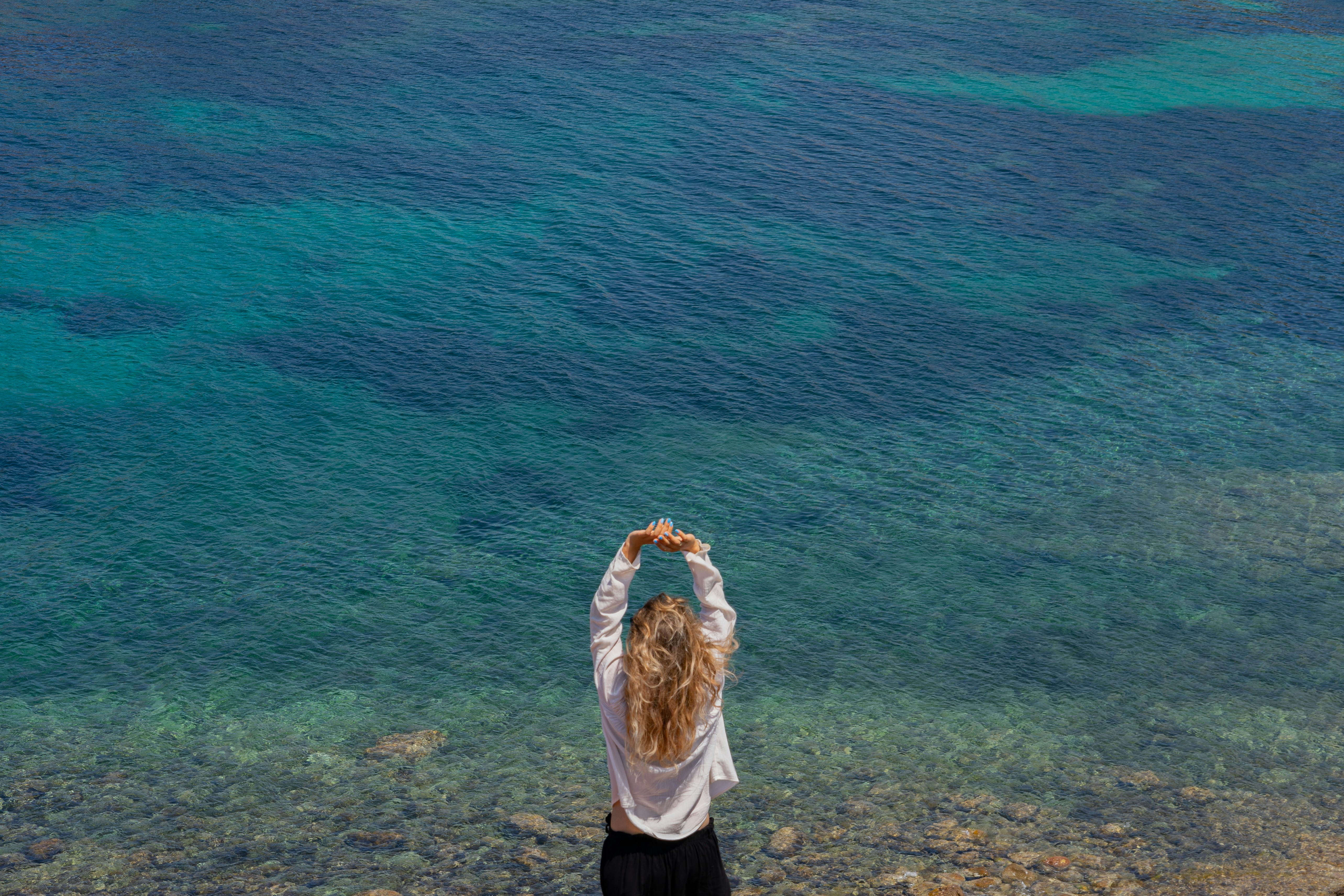 Teal Shoreline Reverie: Hands Raised Toward the Open Sea