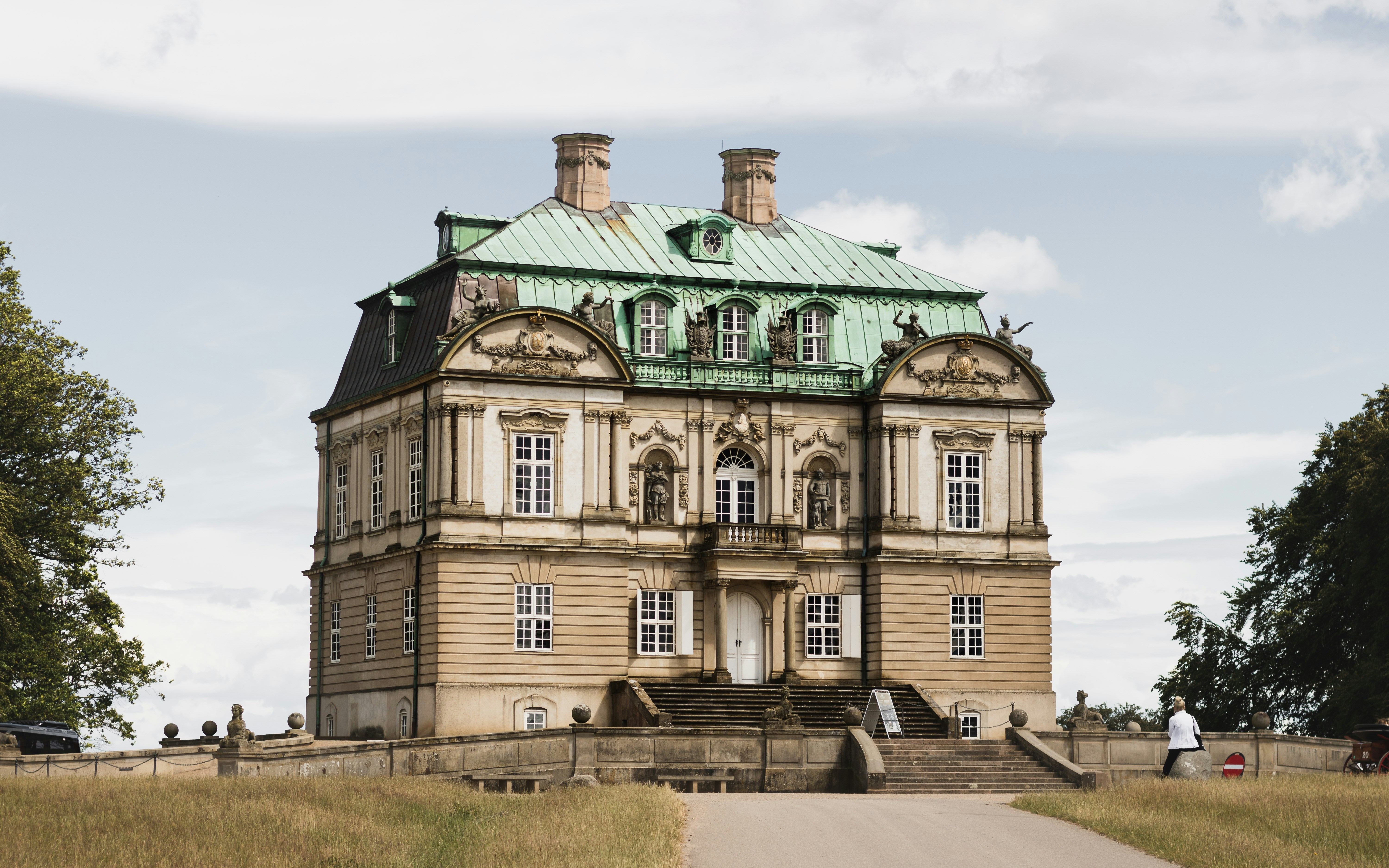 stately manor on elevated grounds with green copper roof
