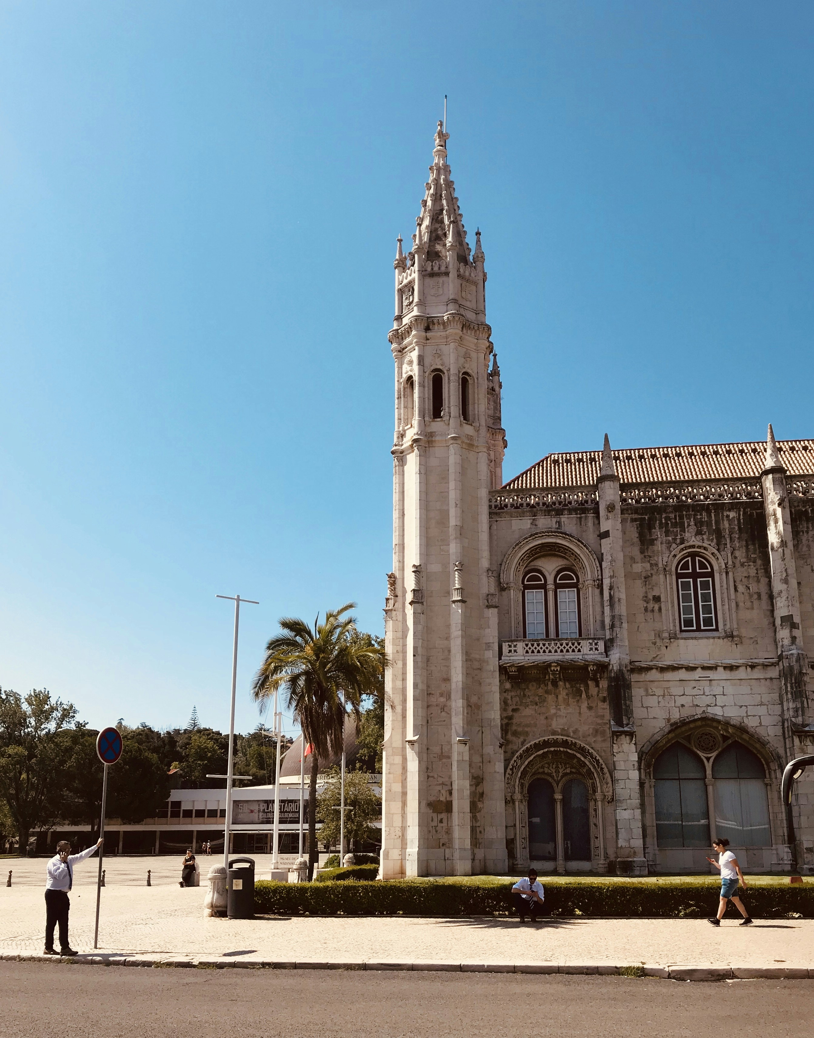 woman walking beside brown building towards to man who seats beside plant during daytimeSuad Kamardeen