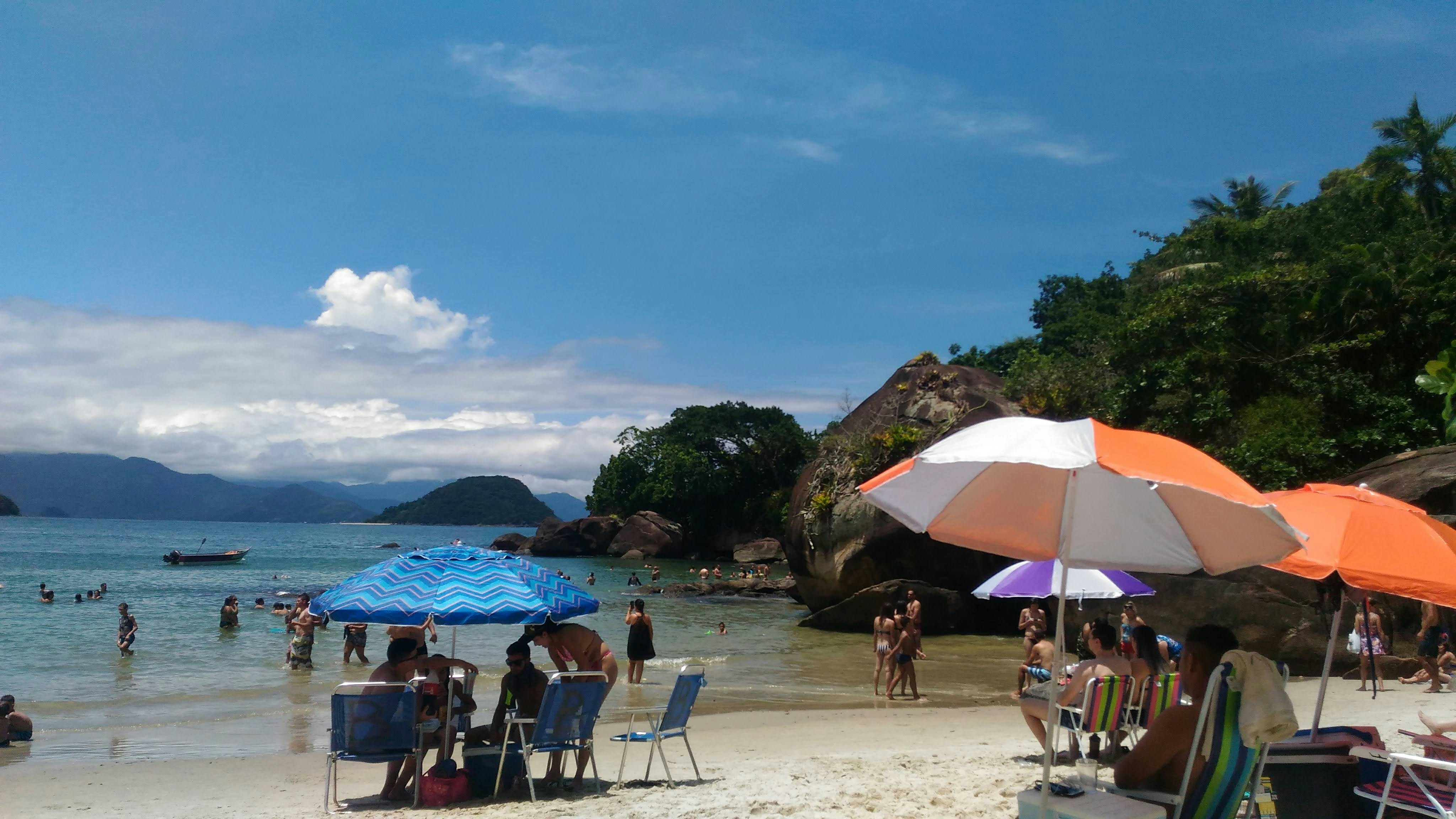 Beachgoers enjoy a sunny day with vibrant umbrellas dotting the sandy shore.