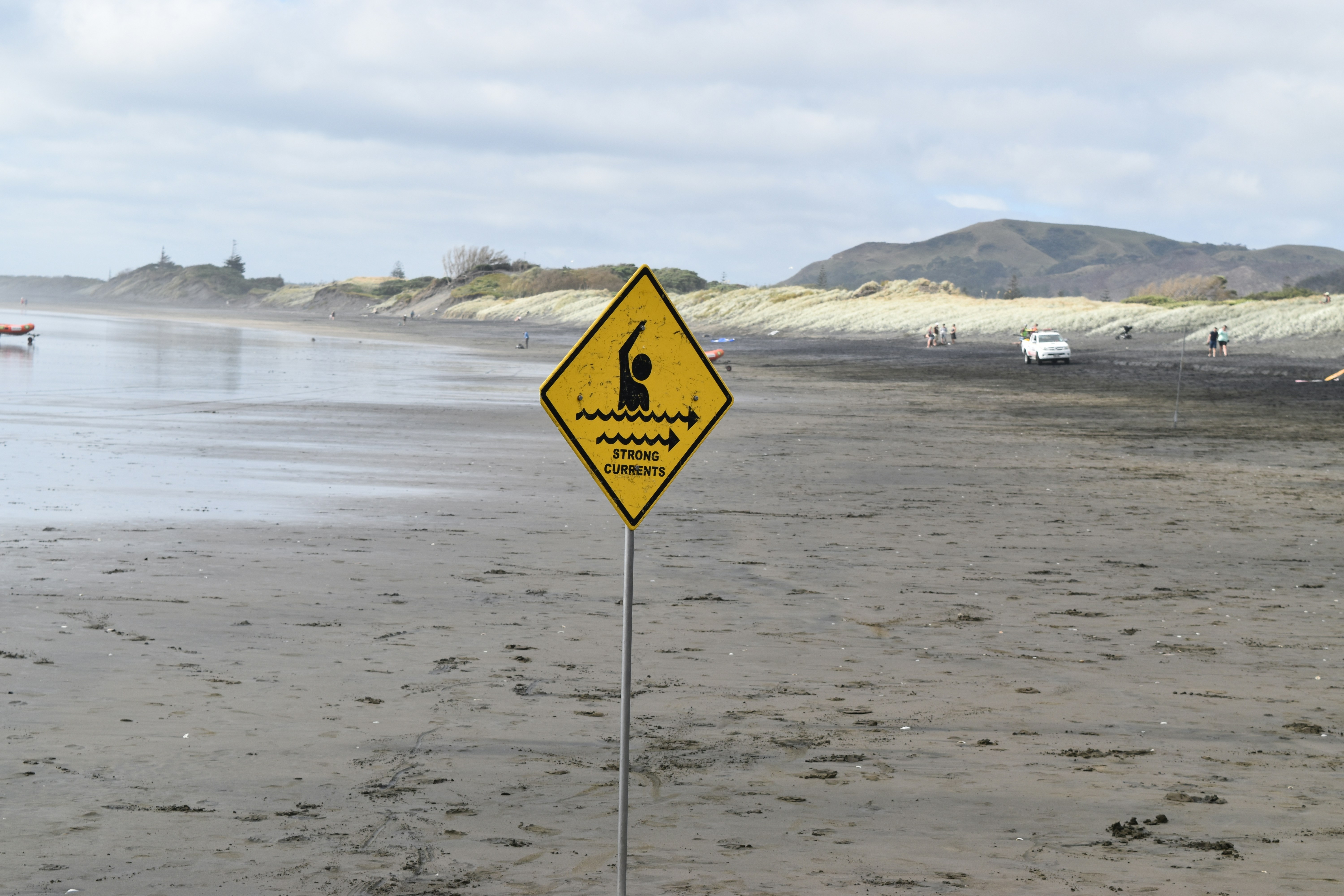 Yellow Warning Sign Anchors the Quiet Beach Against Strong Currents