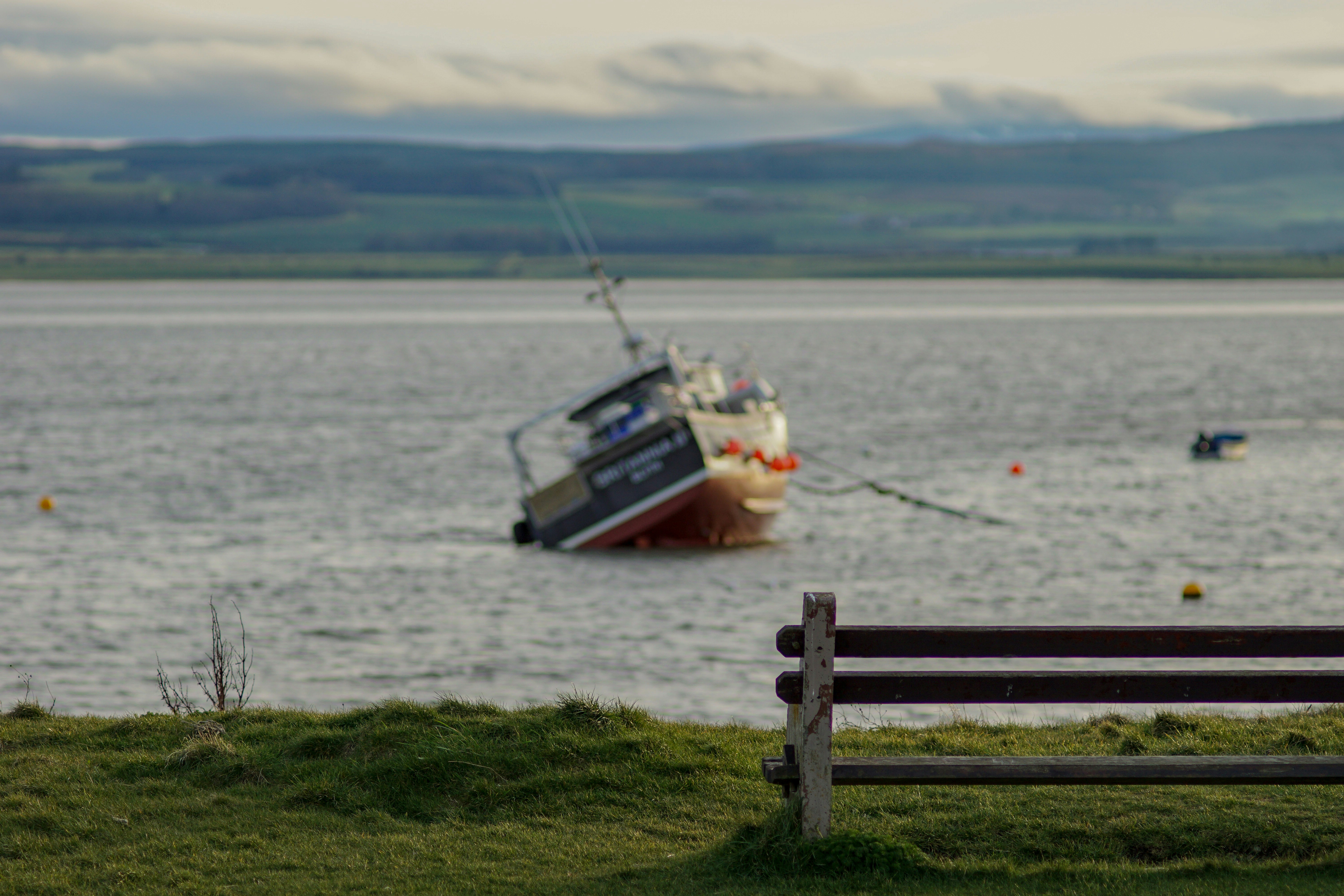 Harbor Tilt: A Tilted Boat Anchored Beyond a Weathered Bench