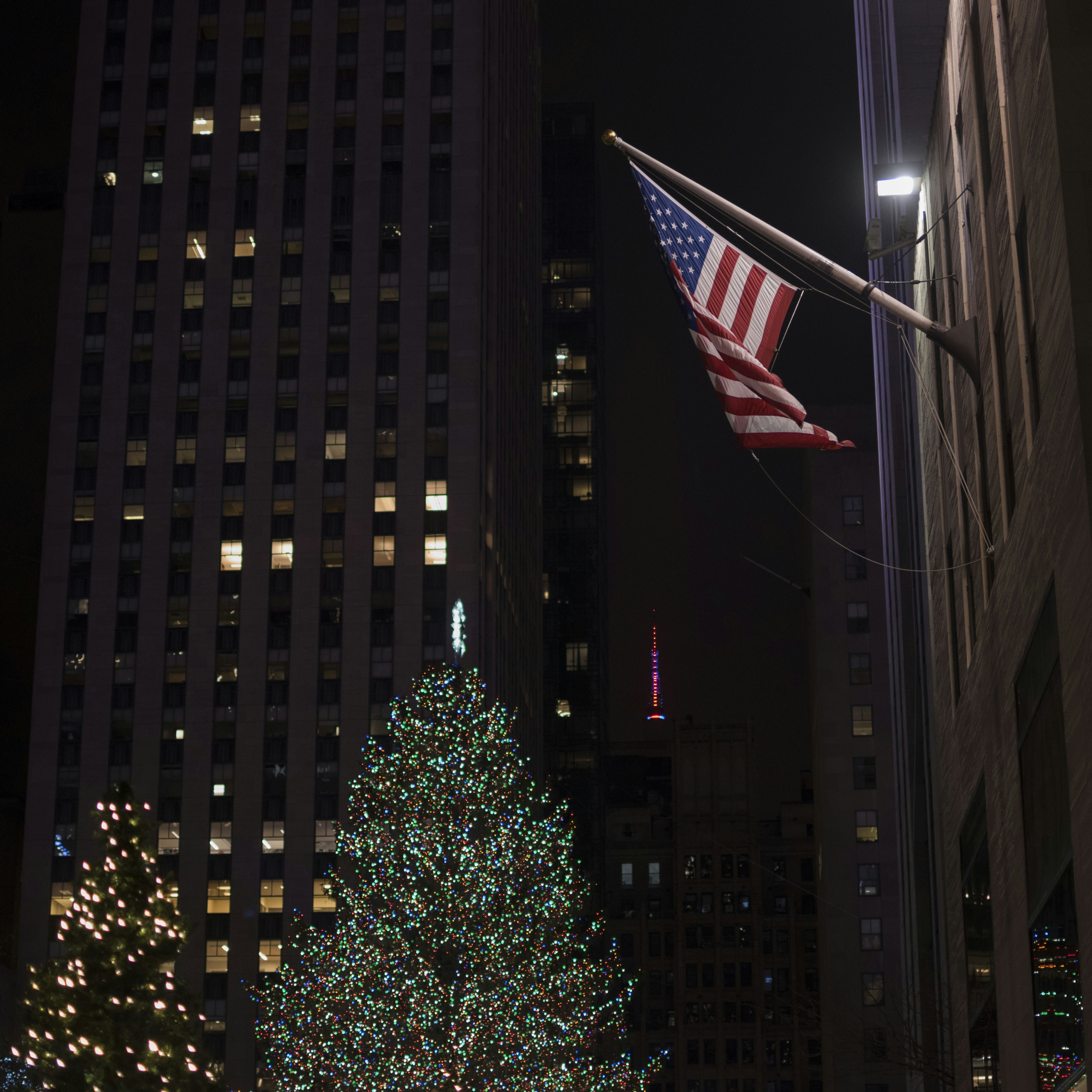American Nightfall: Flag, Lights, and a Christmas Tree in a City Spine