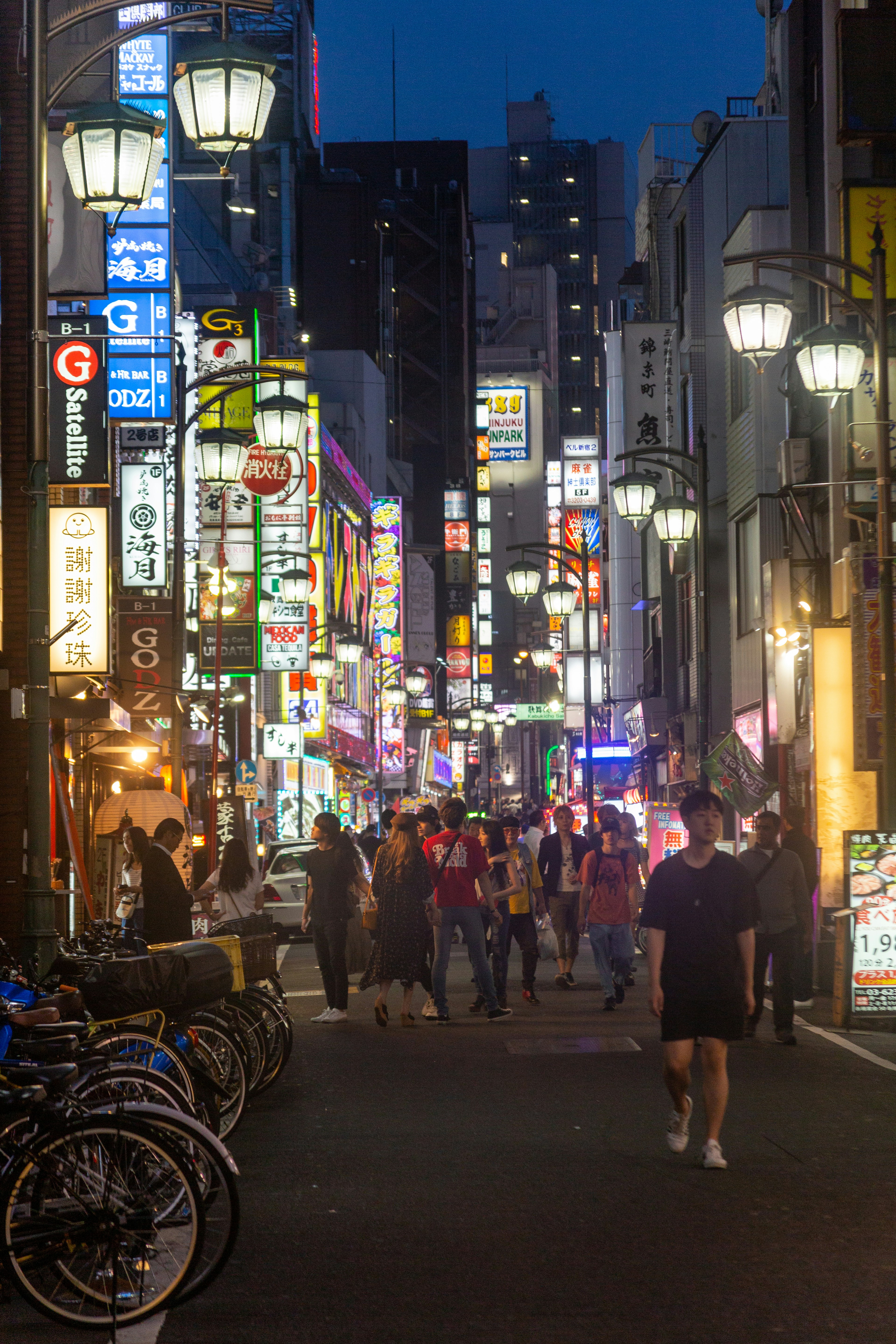 Bustling street scene illuminated by vibrant neon signs in a lively urban setting at dusk.