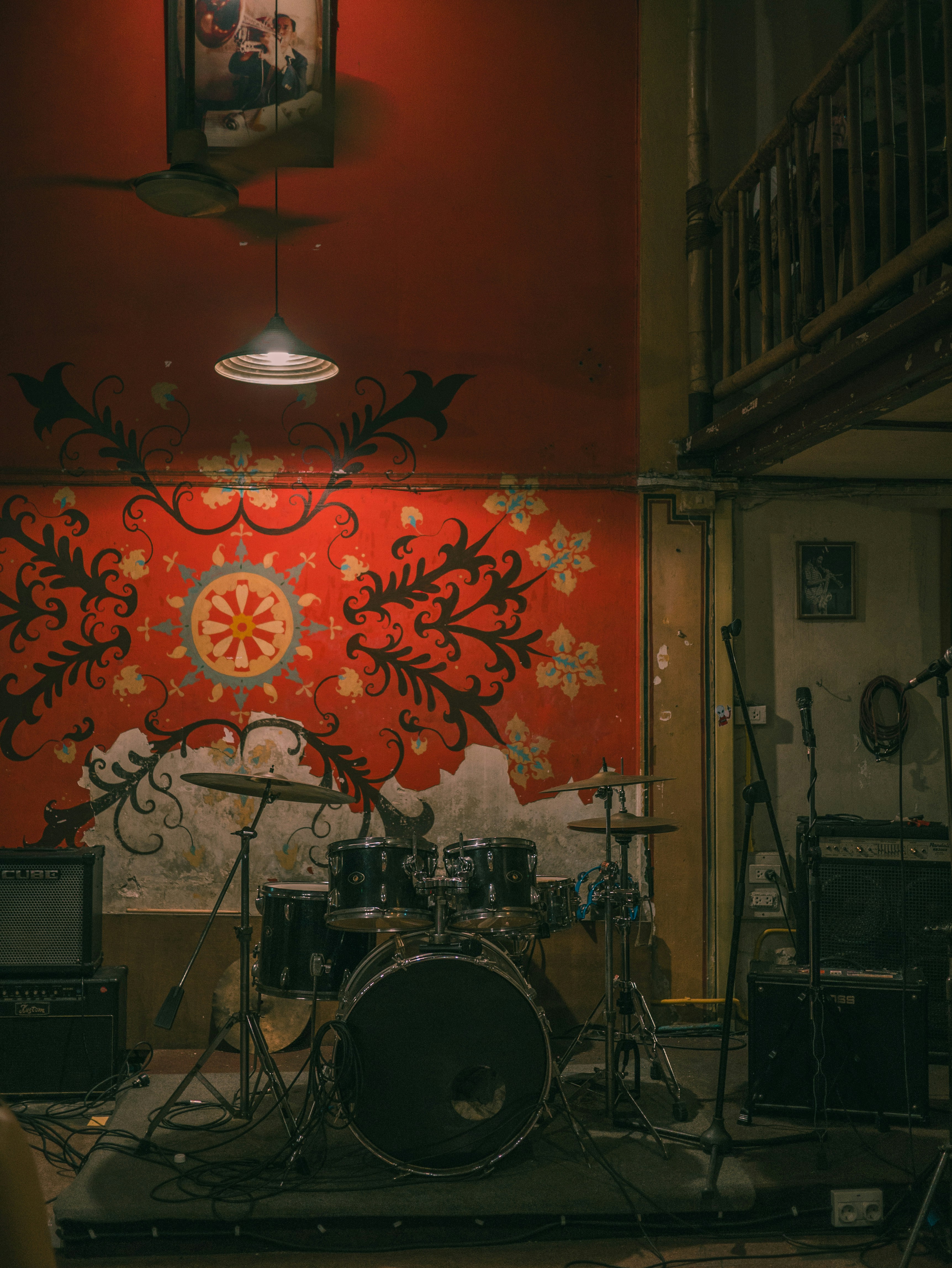 Crimson Mural, Quiet Beats: A Drum Kit Anchored by Colorful Stage Art