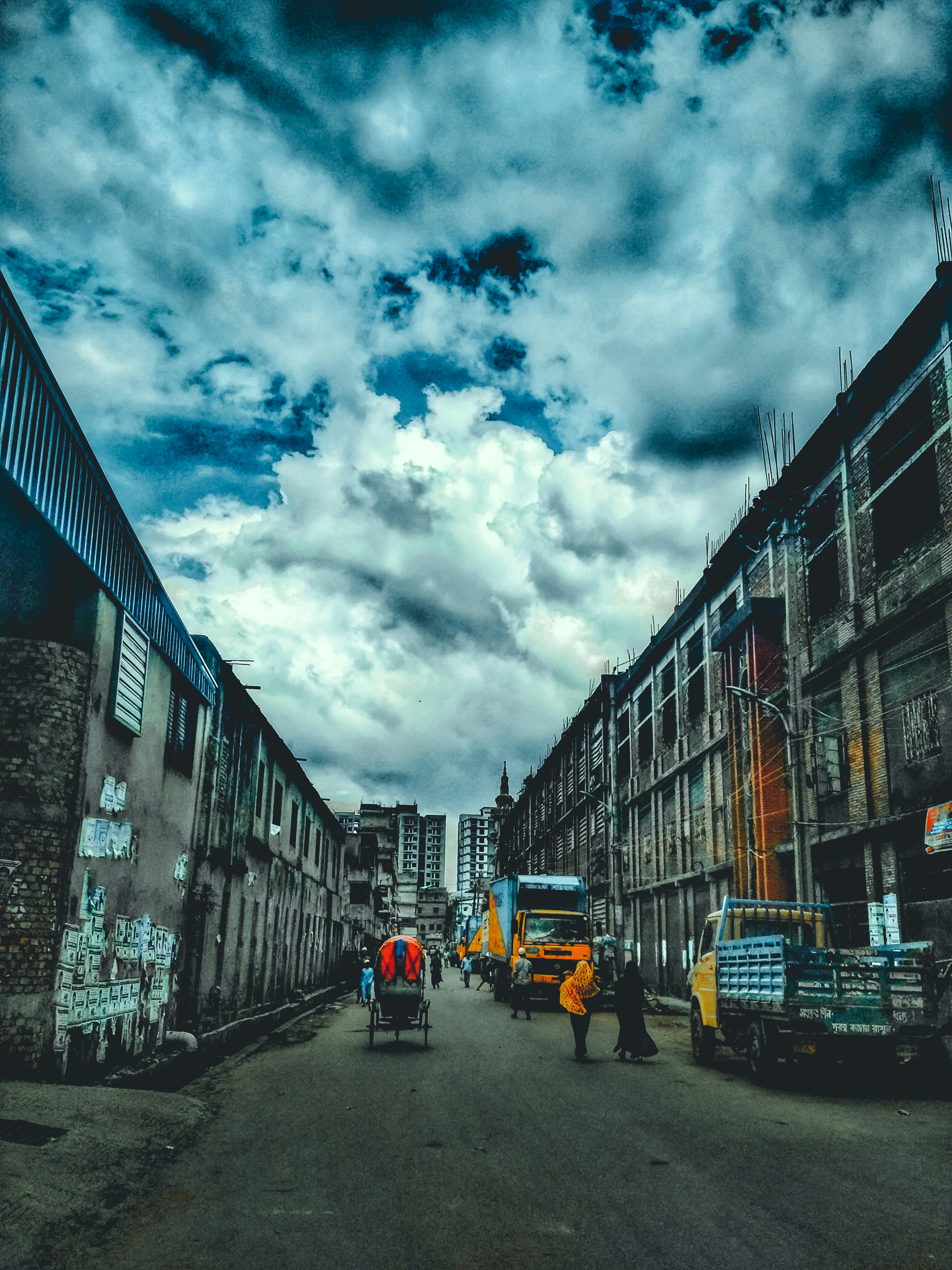Convergence Under Clouded Skies: The Yellow Truck Anchors an Urban Alley
