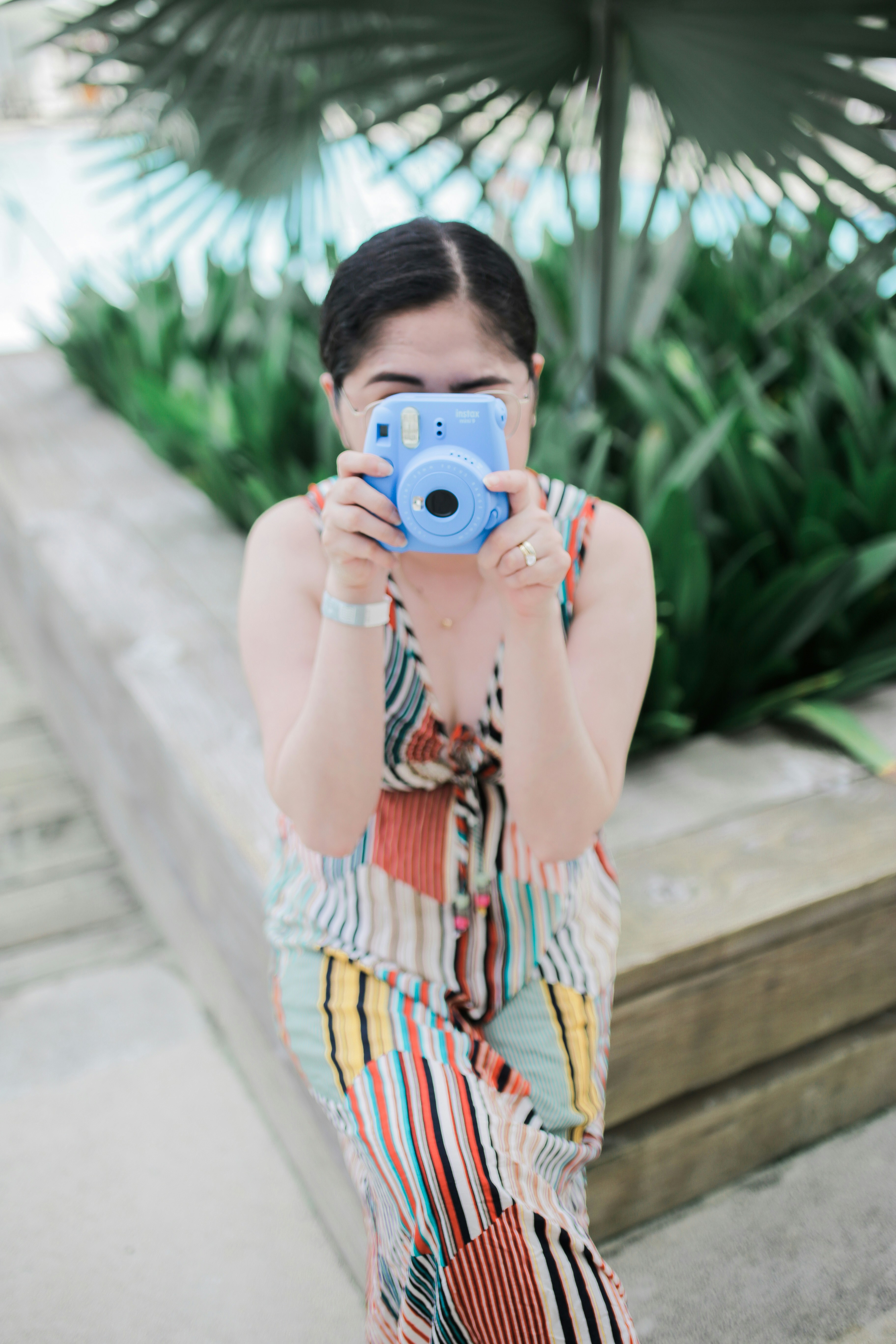 Blue Polaroid Moment: A Girl with a Polaroid in a Tropical Frame